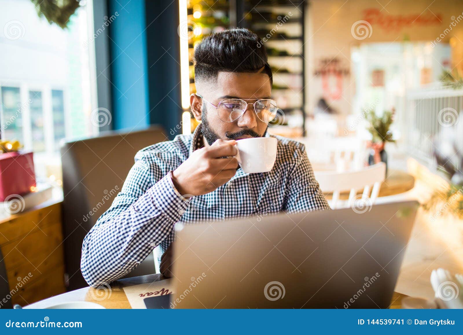 Young Indian Man Drinking Coffee in Cafe and Using Laptop in Cafe Stock ...