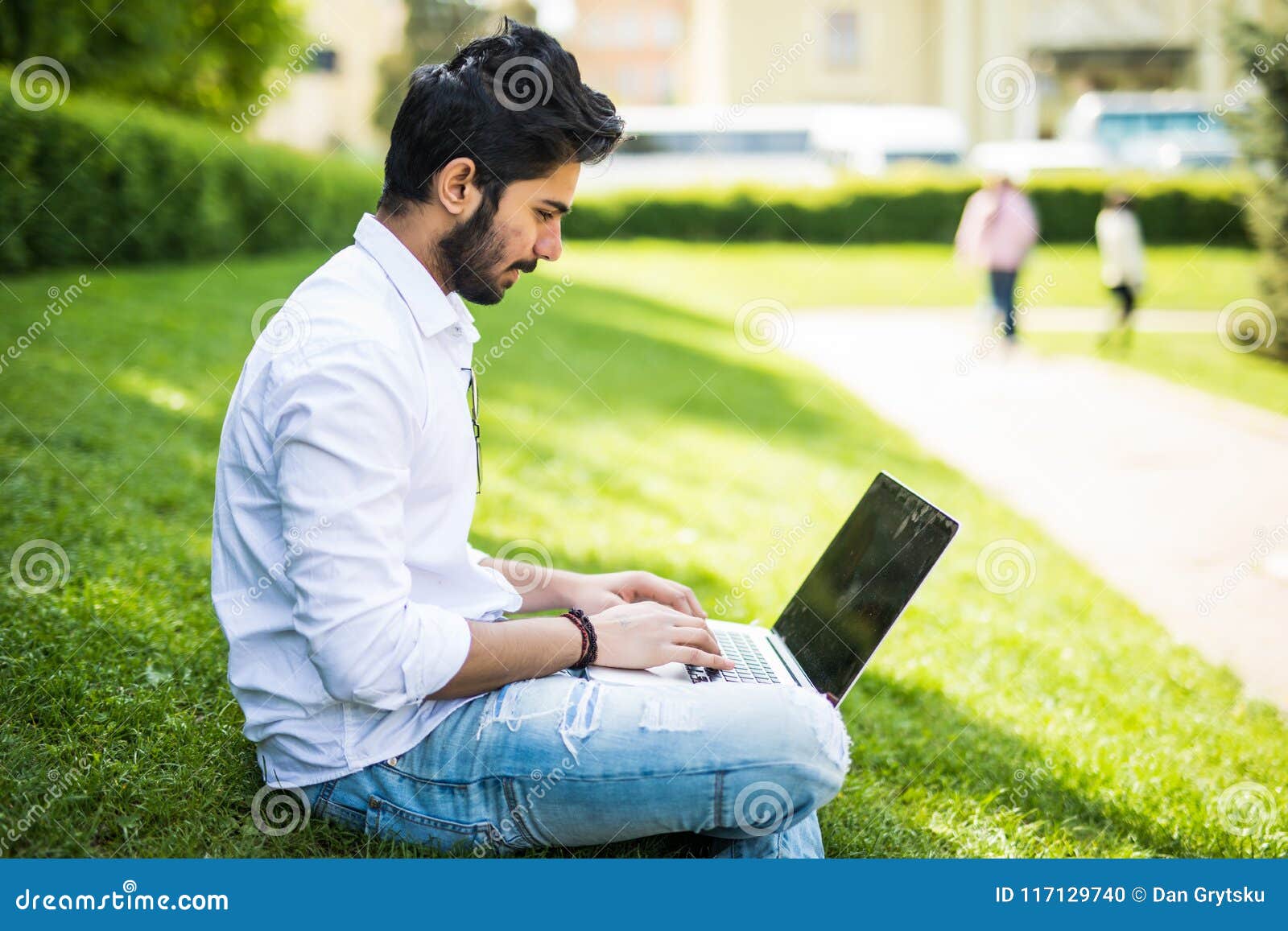 Young Indian Man Using and Typing Laptop Computer in Summer Grass in ...