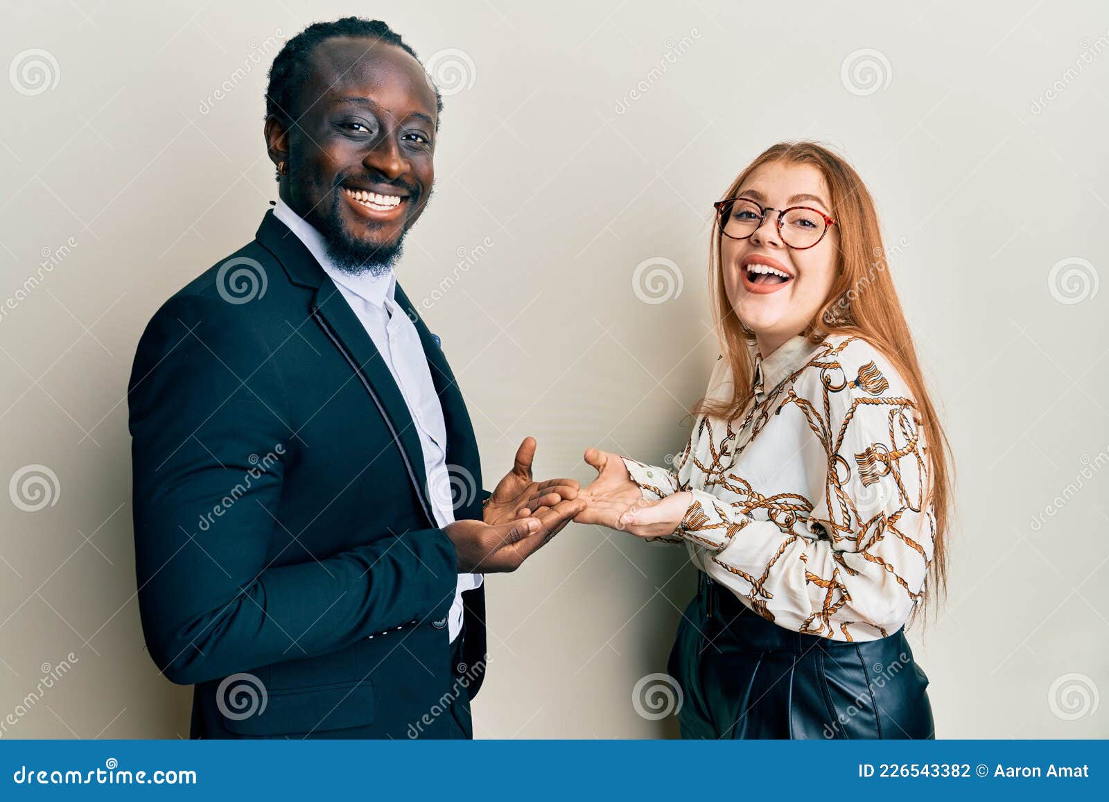 Young Interracial Couple Wearing Business And Elegant Clothes Pointing