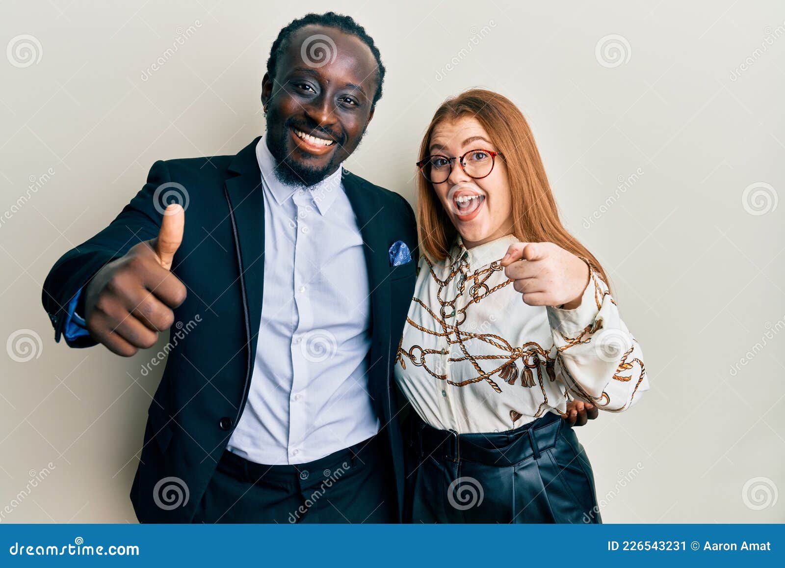 Young Interracial Couple Wearing Business And Elegant Clothes Pointing
