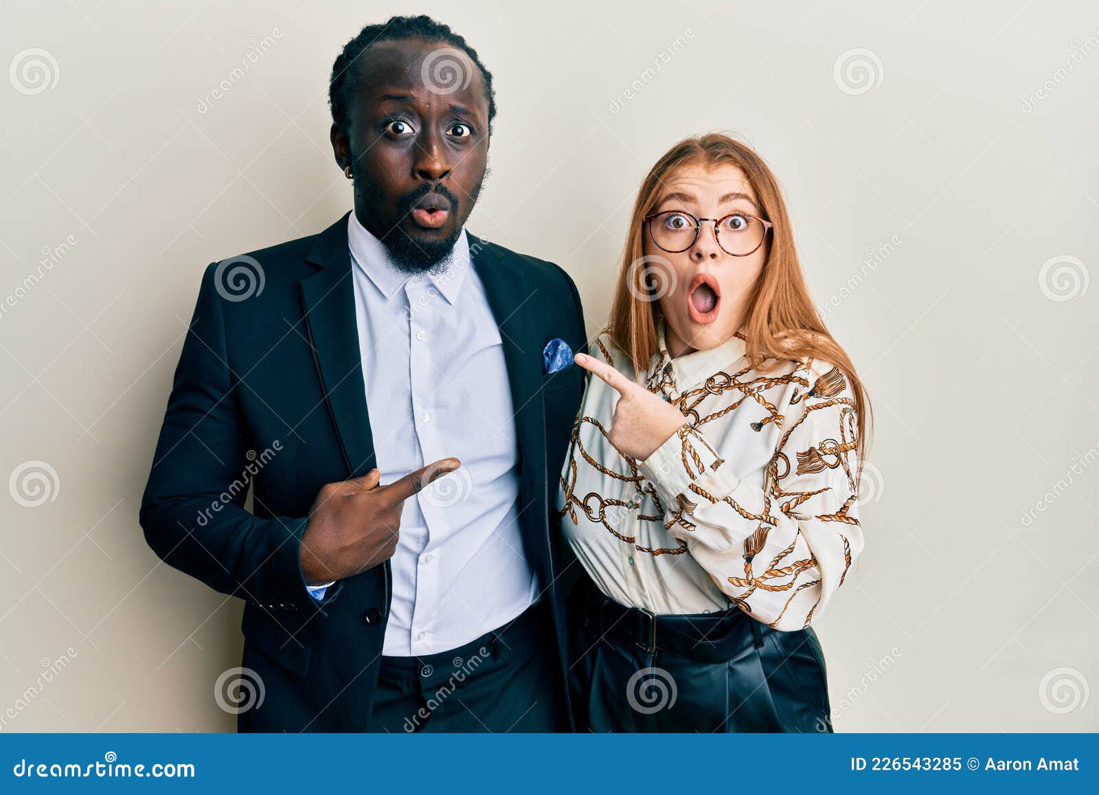 Young Interracial Couple Wearing Business And Elegant Clothes Surprised