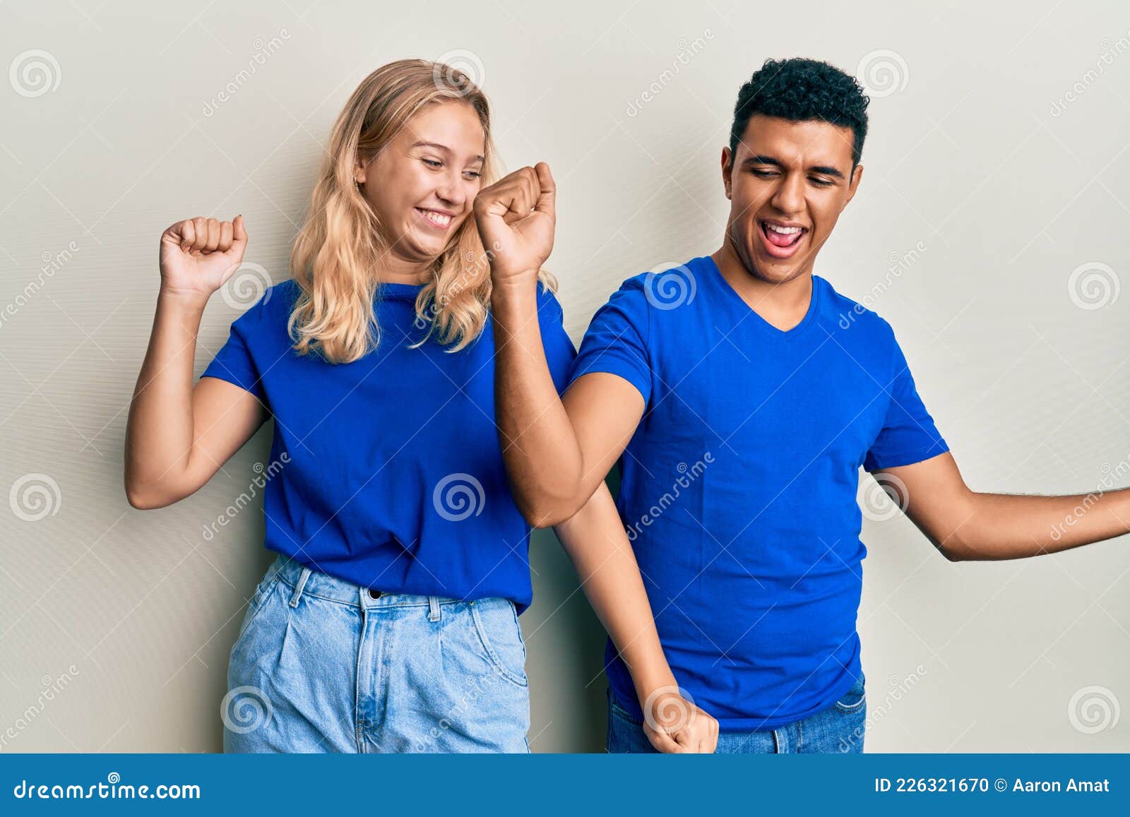 Young Interracial Couple Wearing Casual Clothes Dancing Happy And