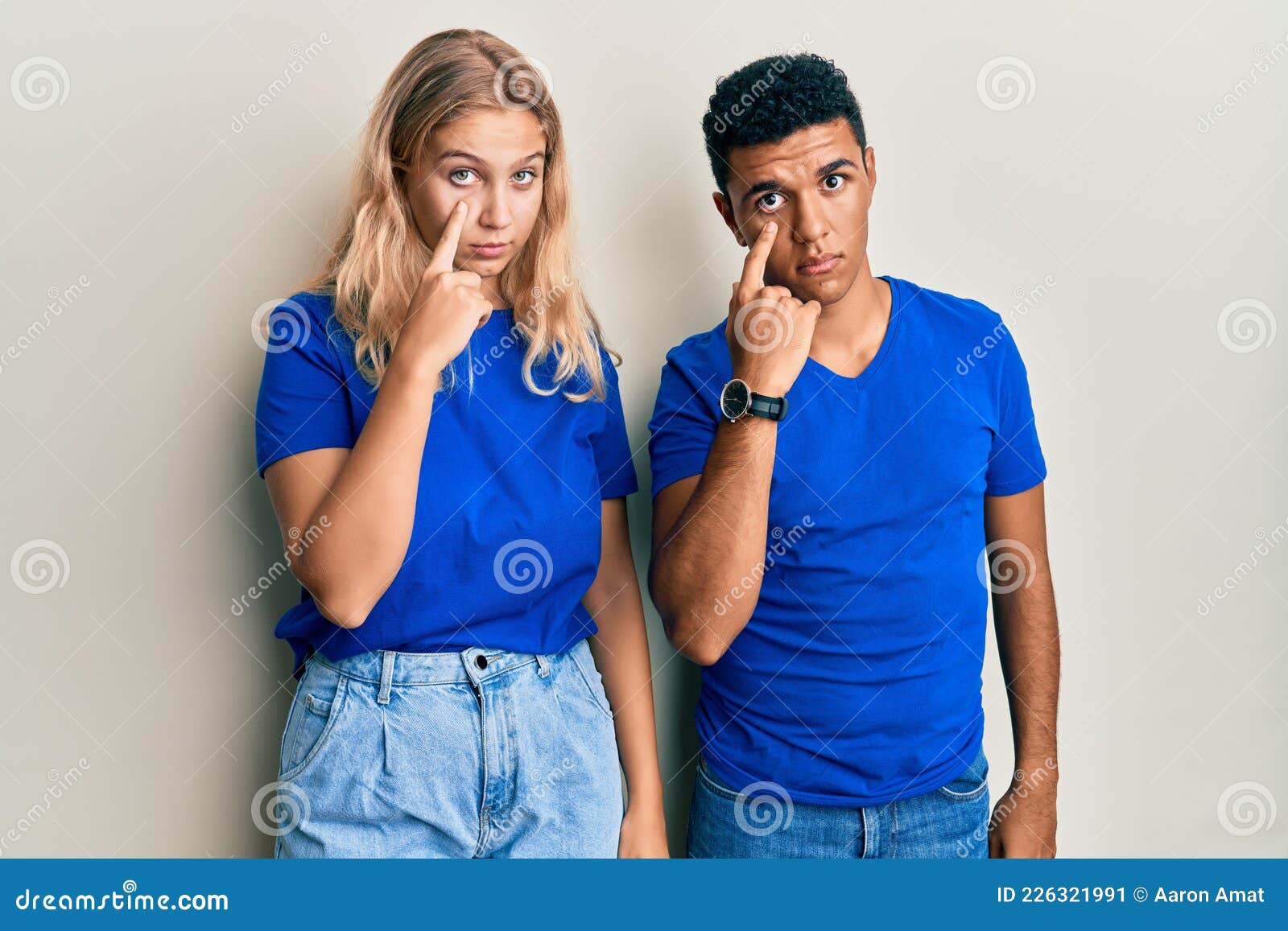 Young Interracial Couple Wearing Casual Clothes Pointing To The Eye