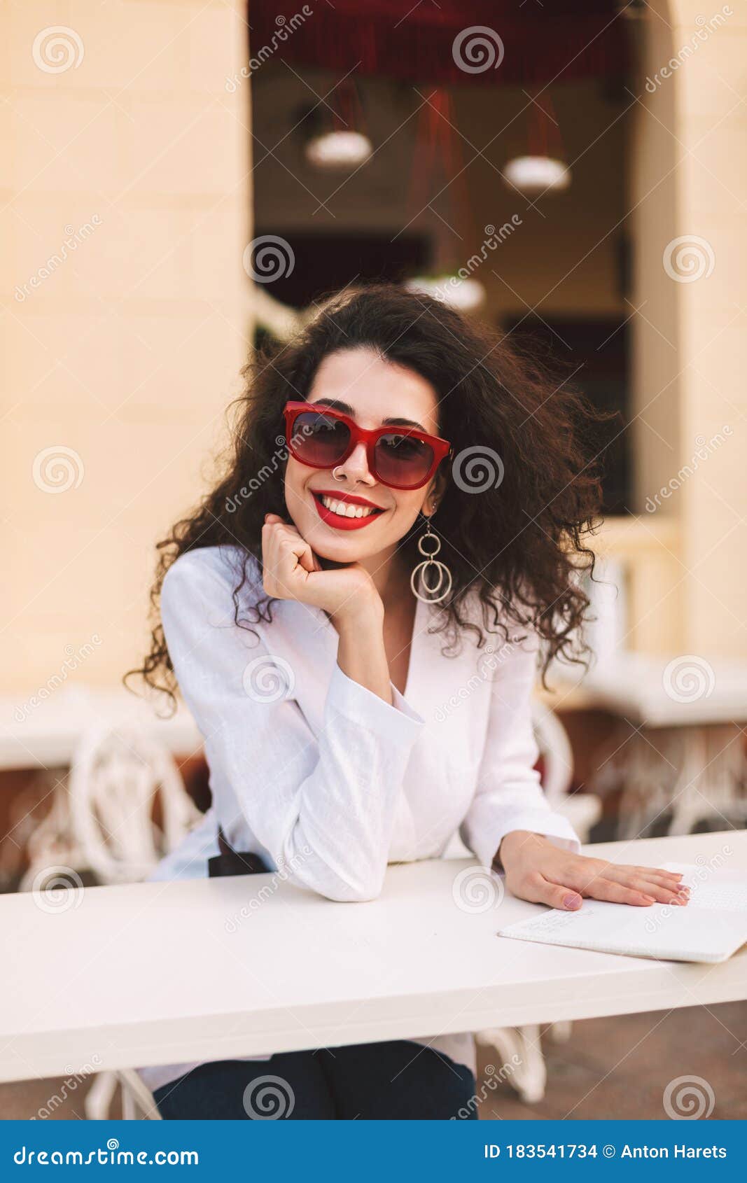 Young Joyful Lady With Dark Curly Hair In Sunglasses Standing And