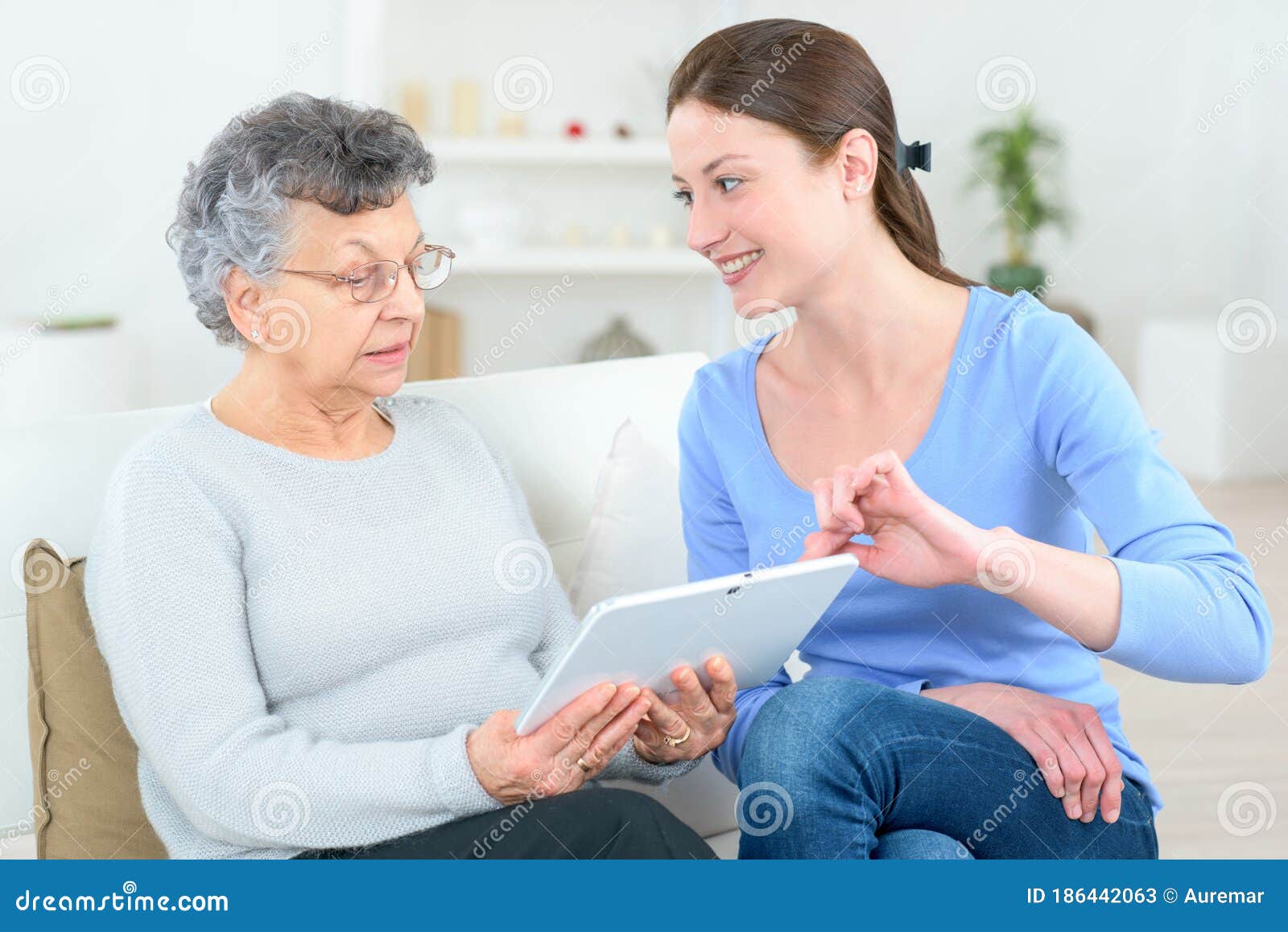 Young Lady Helping Elderly Woman Use Digital Tablet Stock Image - Image ...
