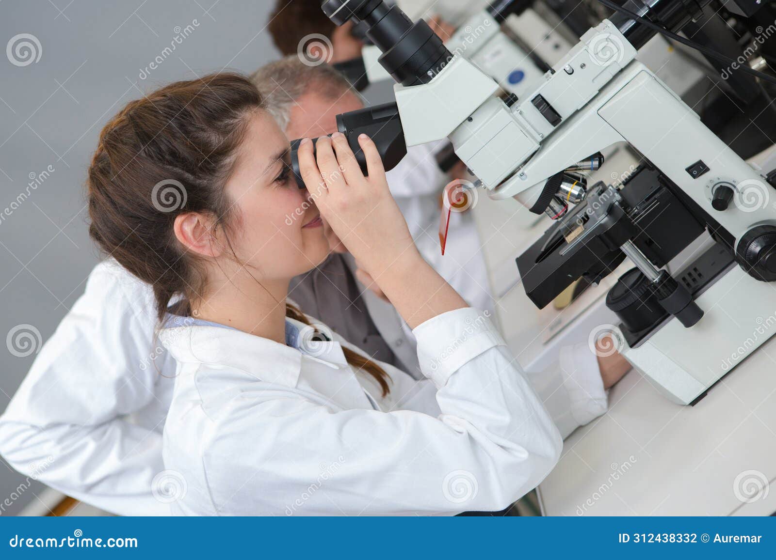 Young Lady Looking through Microscope in Science Lab Stock Photo ...