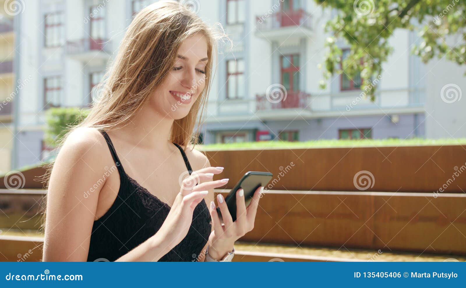 Young Lady Using a Phone in Town while Walking Stock Photo - Image of ...