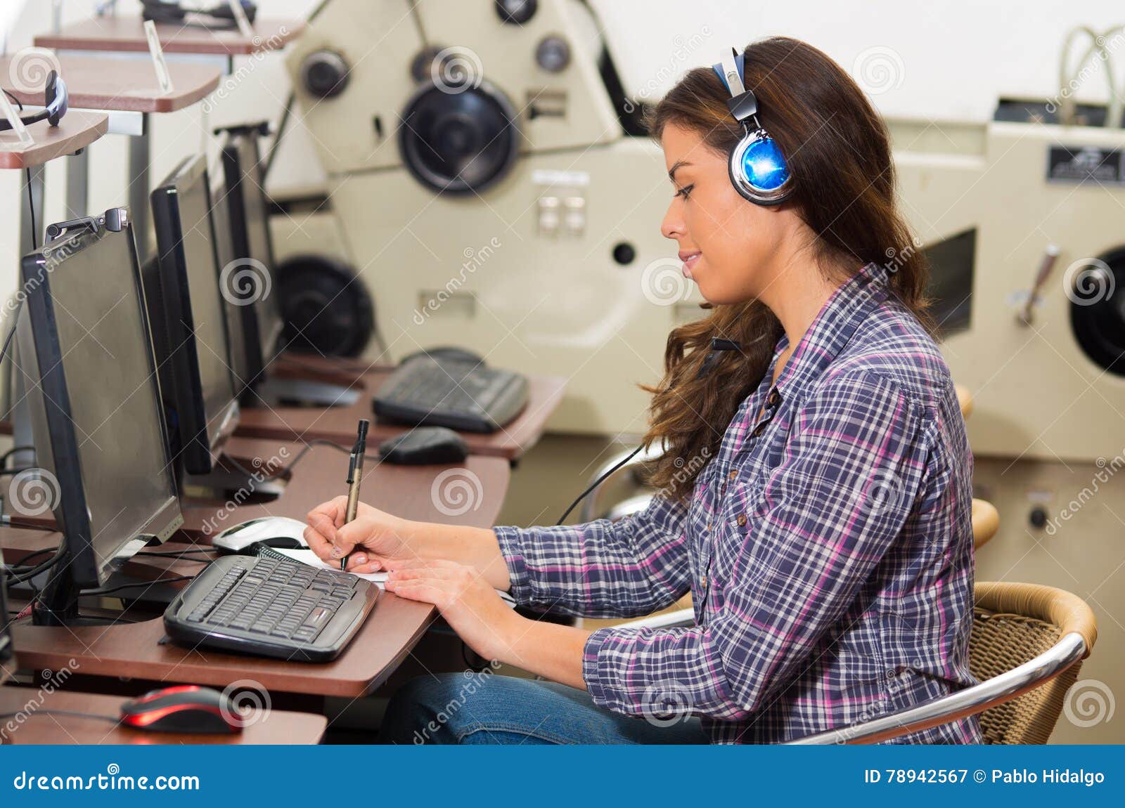 Young Lady Writting Some Notes on a Notebook Next To a Keyboard Stock ...