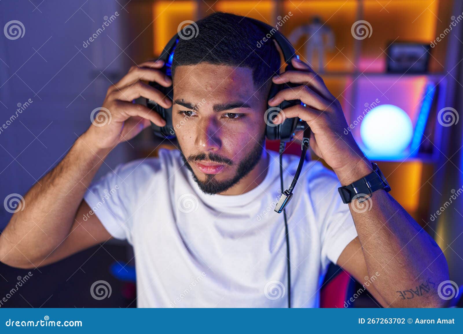 Young Latin Man Streamer Sitting on Table with Serious Expression at ...