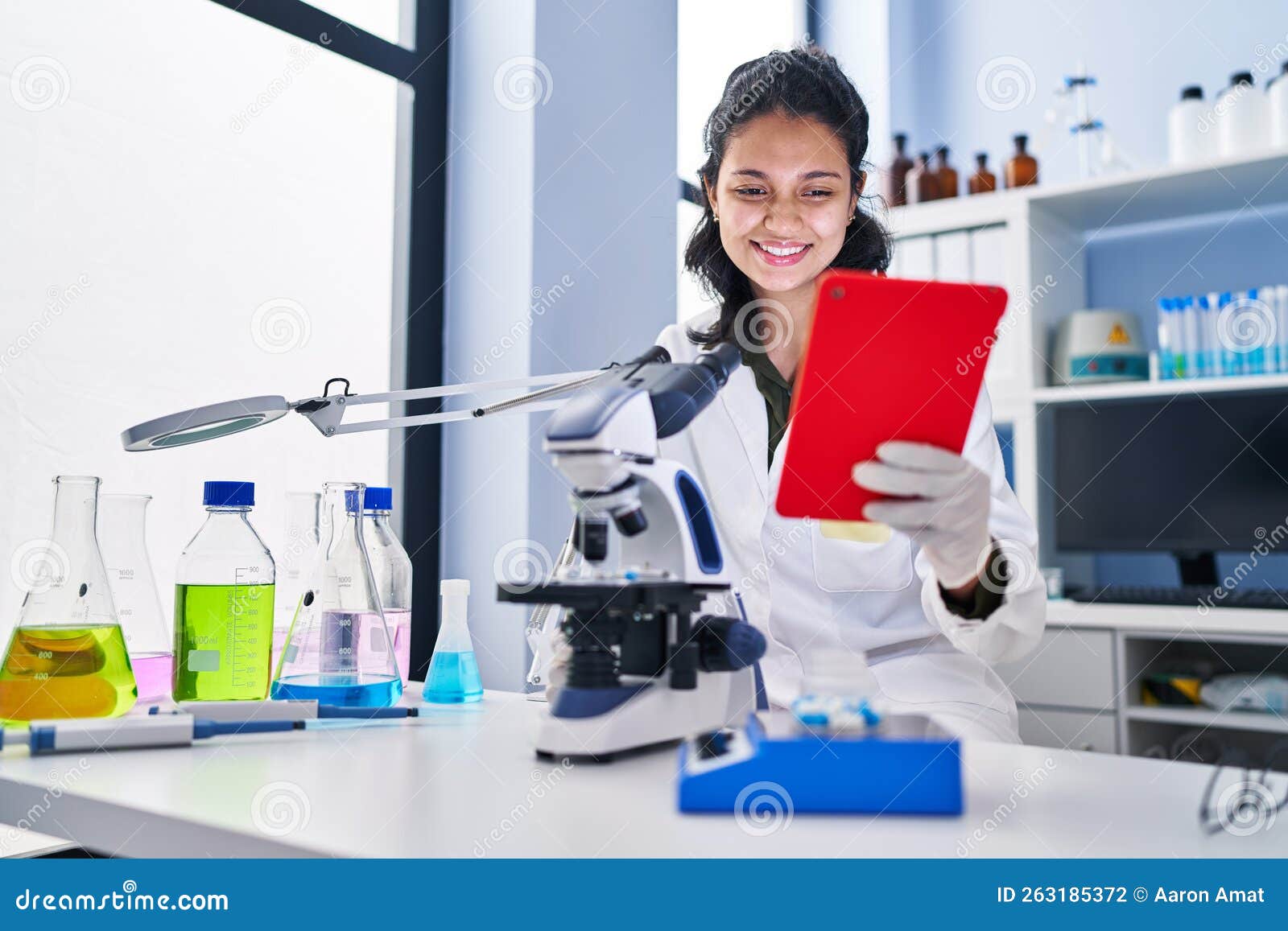 Young Latin Woman Scientist Using Microscope and Touchpad at Laboratory ...