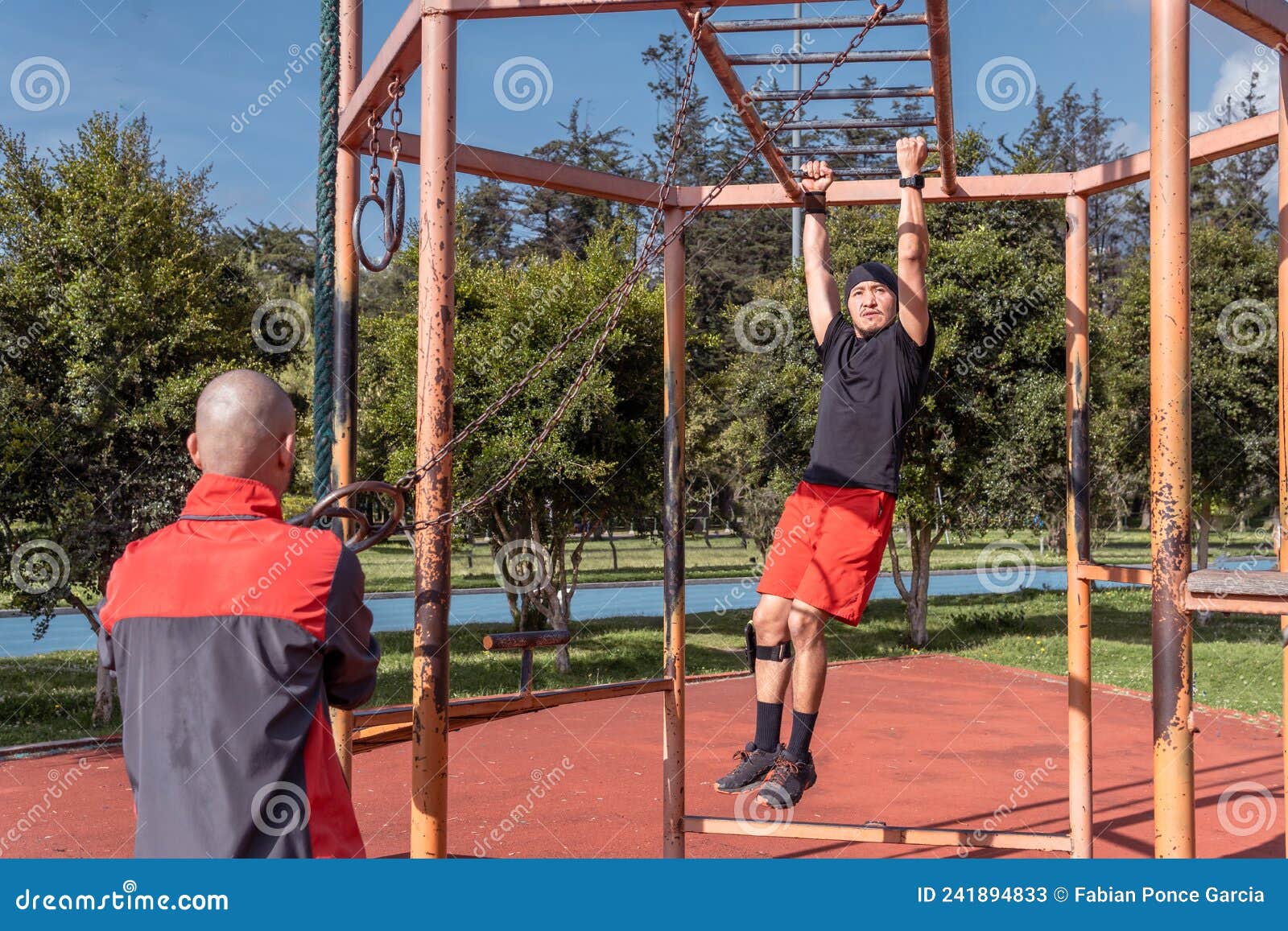 A Young Latino Man Crosses the Monkey Bar in His Exercise Routine while ...