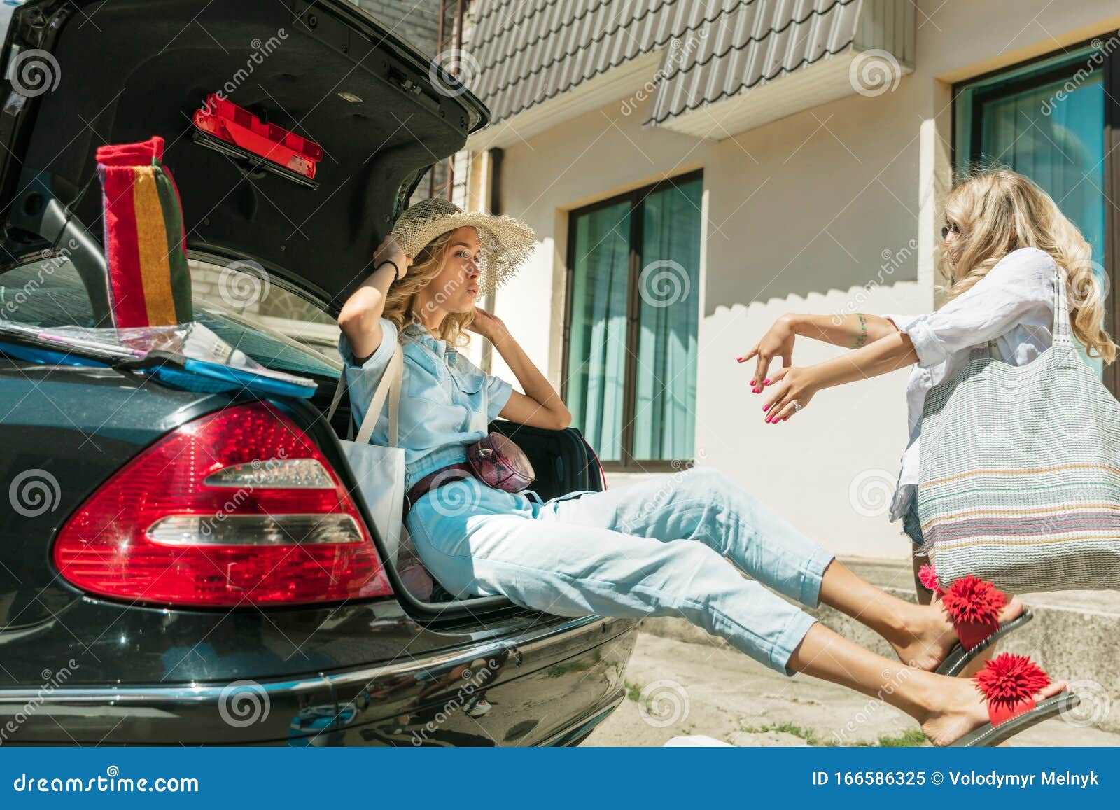 Young Lesbian`s Couple Preparing For Vacation Trip On The Car In Sunny