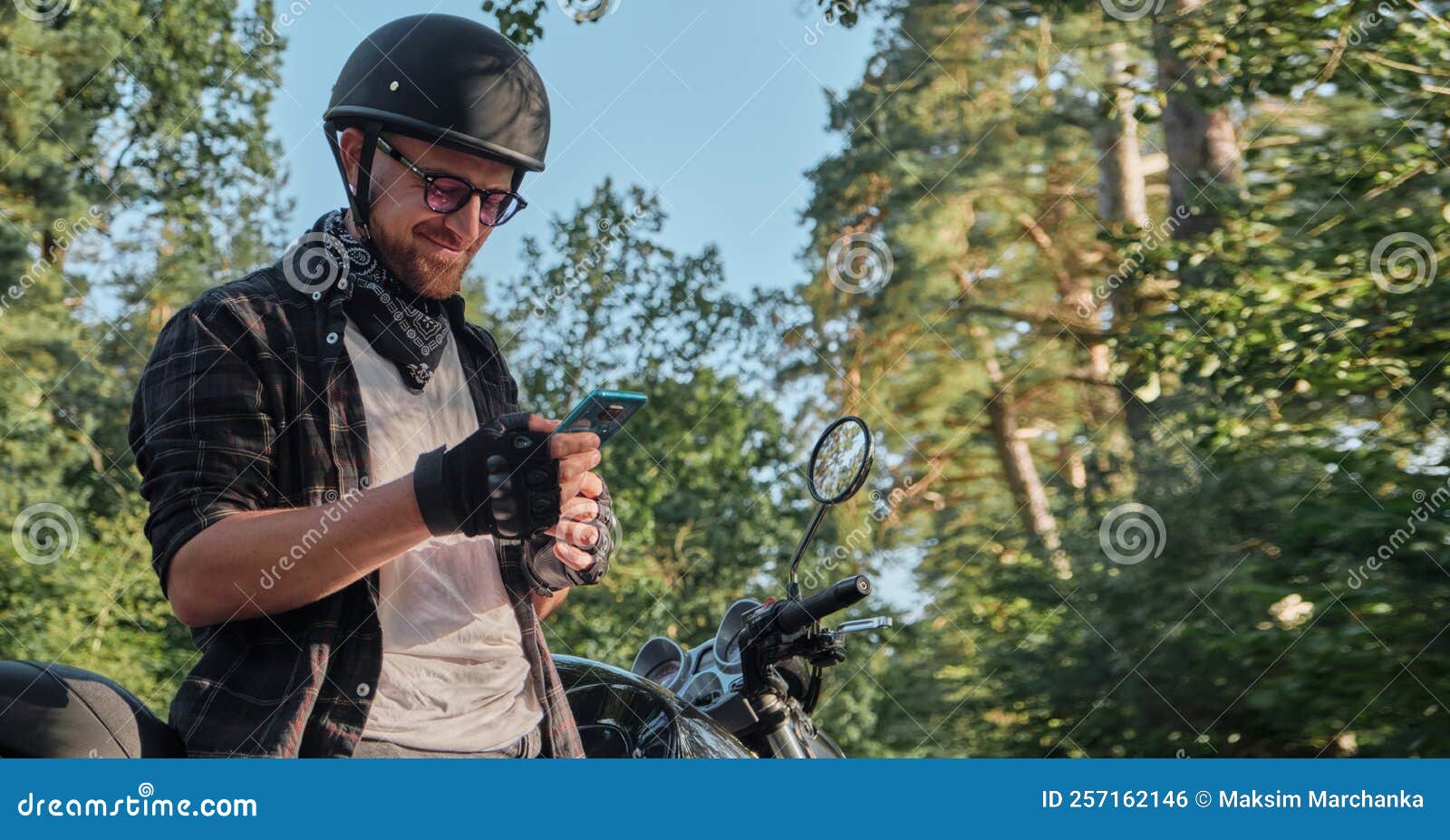 Young Male Biker in Helmet Using Mobile Phone and Smiling Sitting on a ...