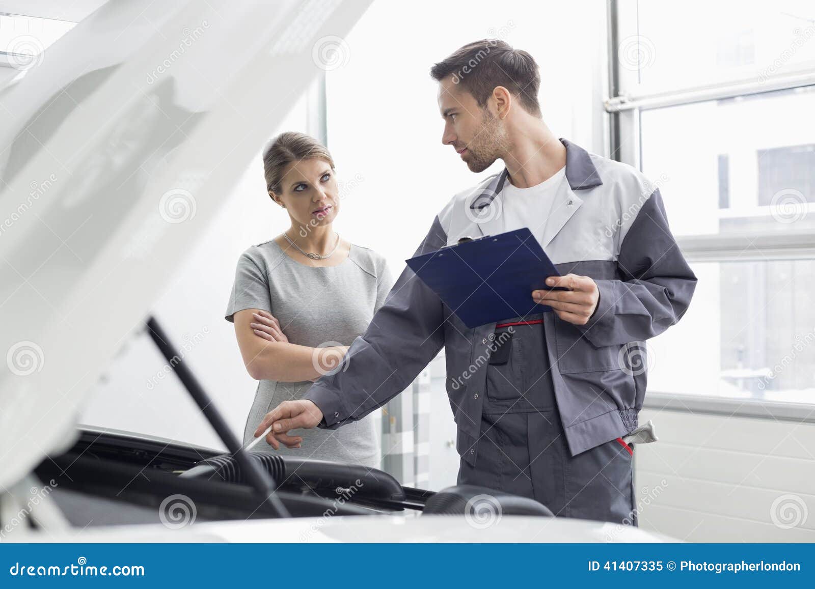 Young Male Engineer Explaining Car Engine To Female Customer in ...
