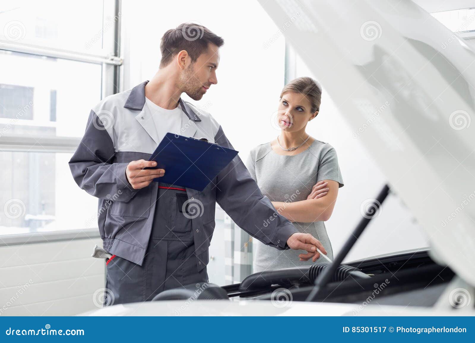 Young Male Engineer Explaining Car Engine To Female Customer in ...