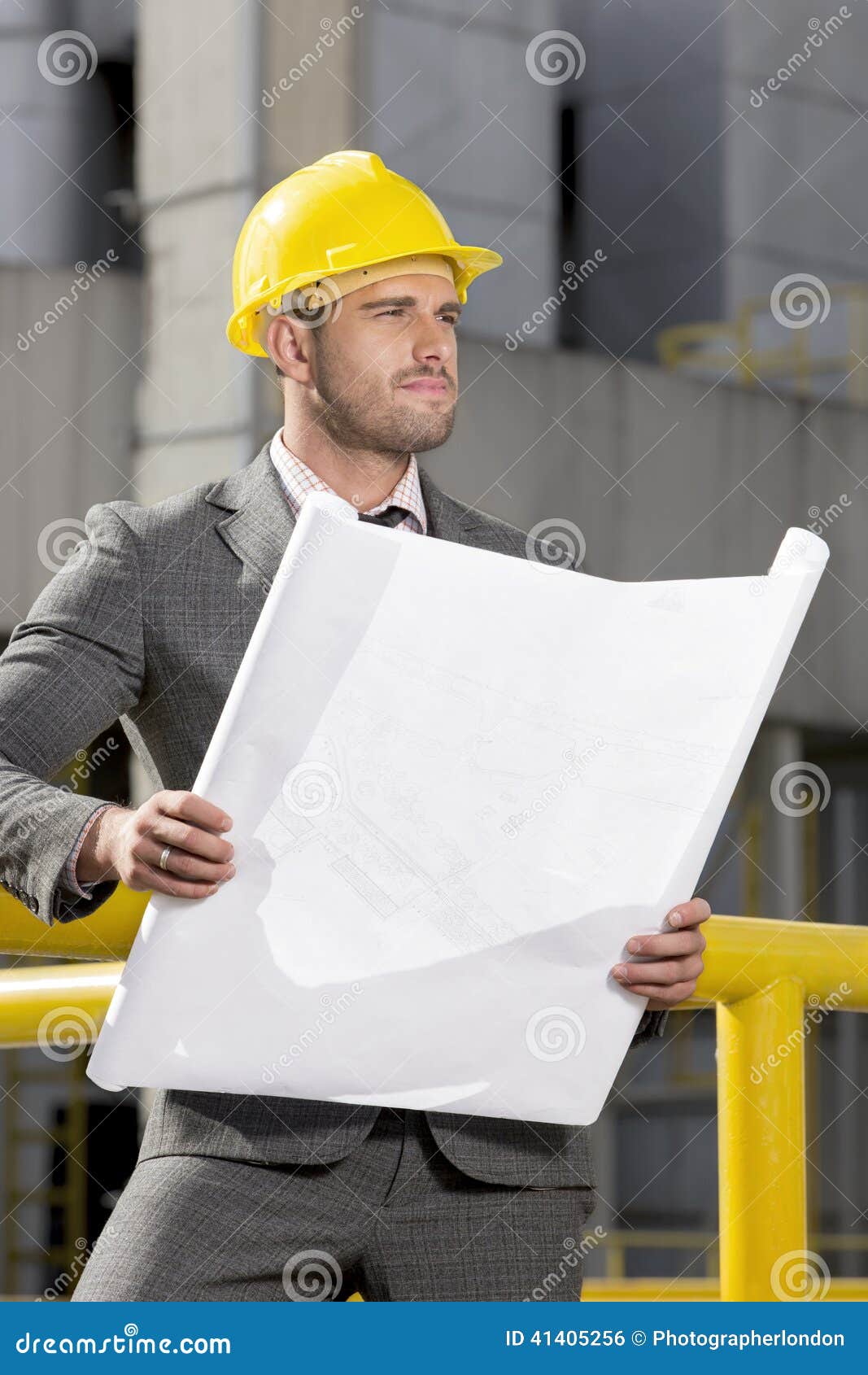 Young Male Engineer Holding Blueprint while Looking Away at ...