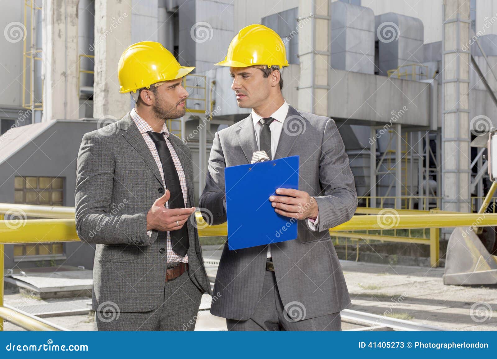 Young Male Engineers with Clipboard Discussing at Construction Site ...
