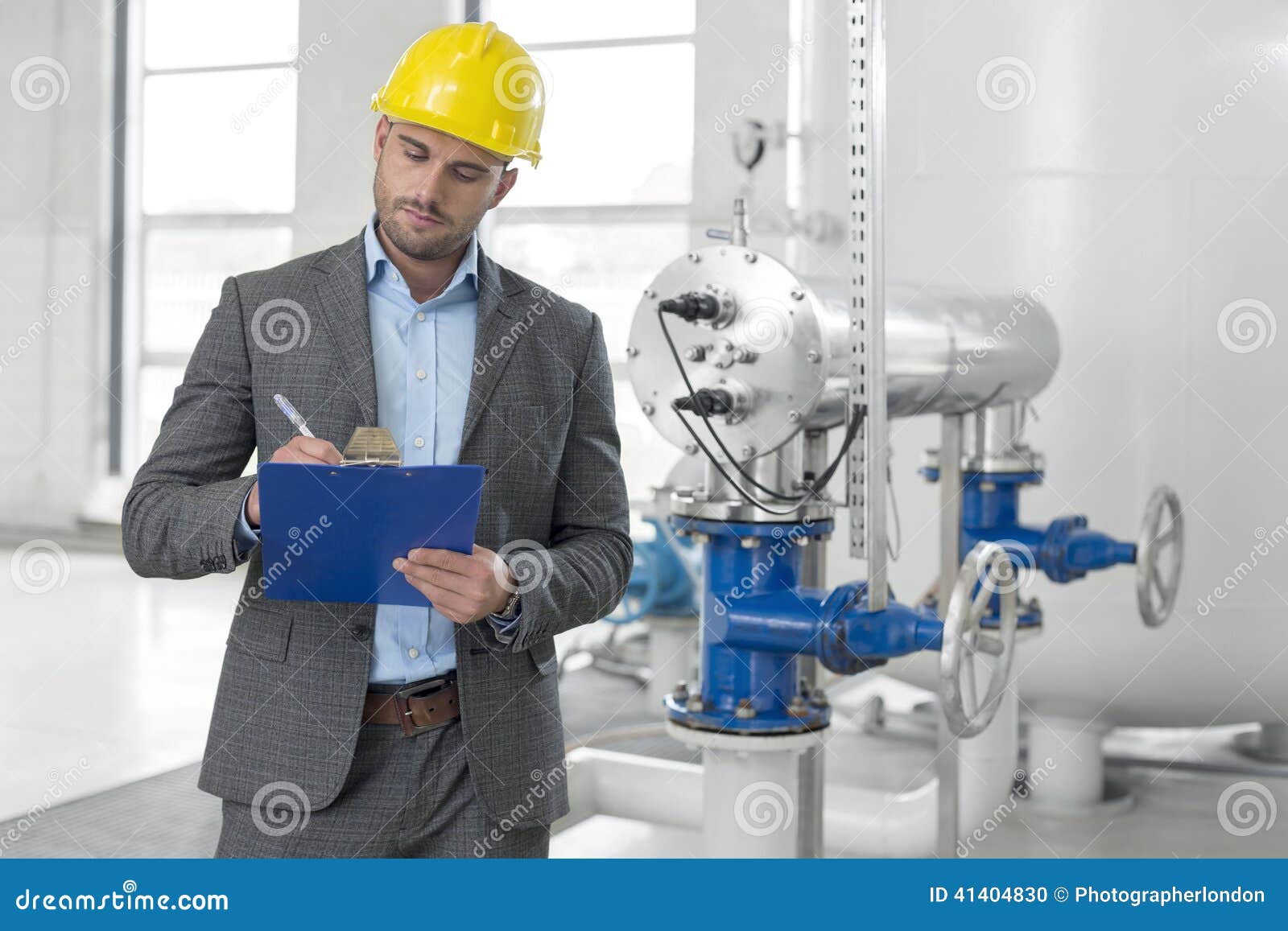 Young Male Manager Writing on Clipboard in Industry Stock Photo - Image ...