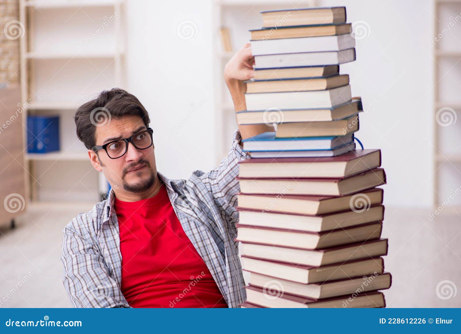 Young Male Student and Too Many Books in the Classroom Stock Photo ...