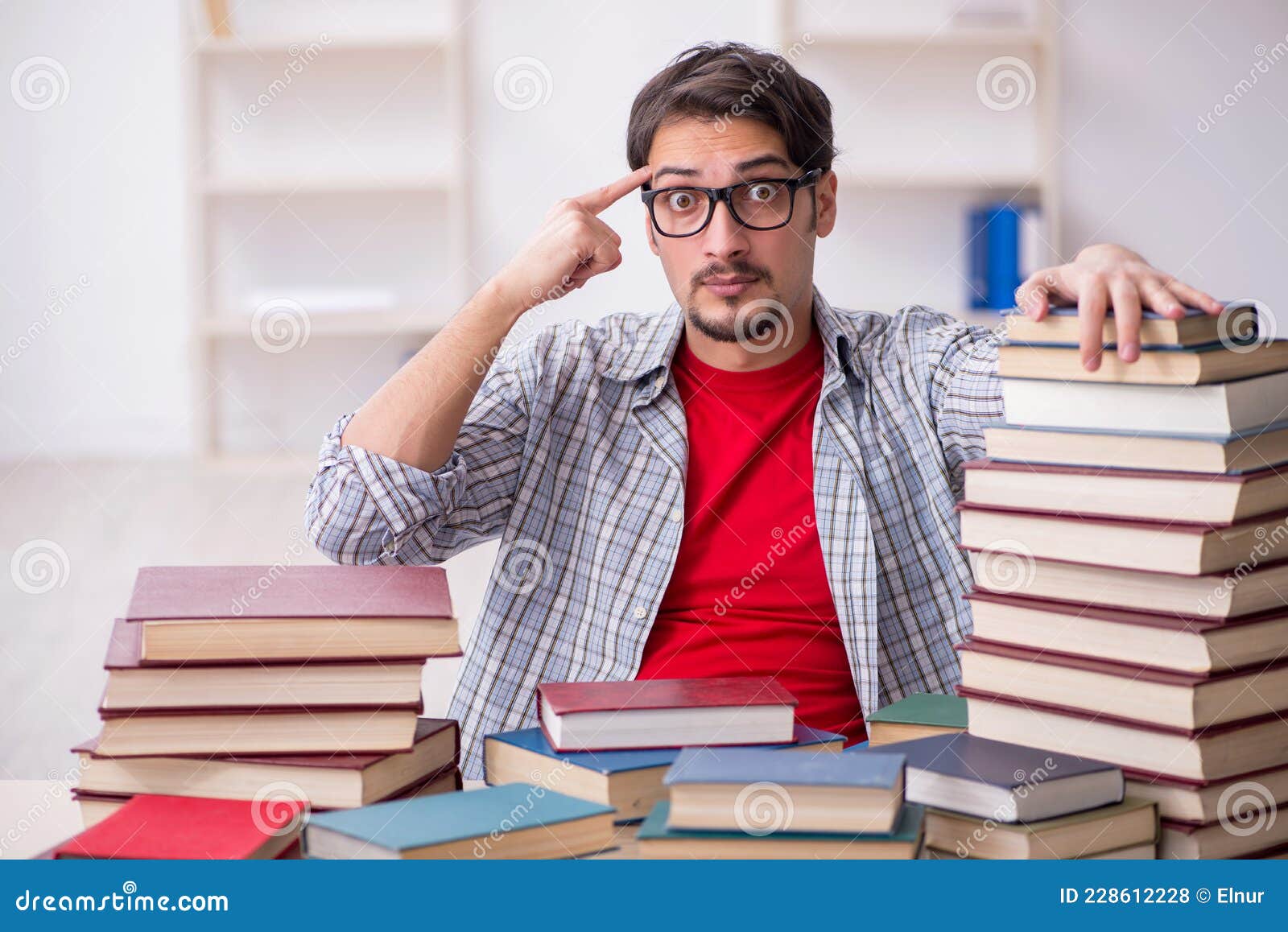 Young Male Student and Too Many Books in the Classroom Stock Photo ...