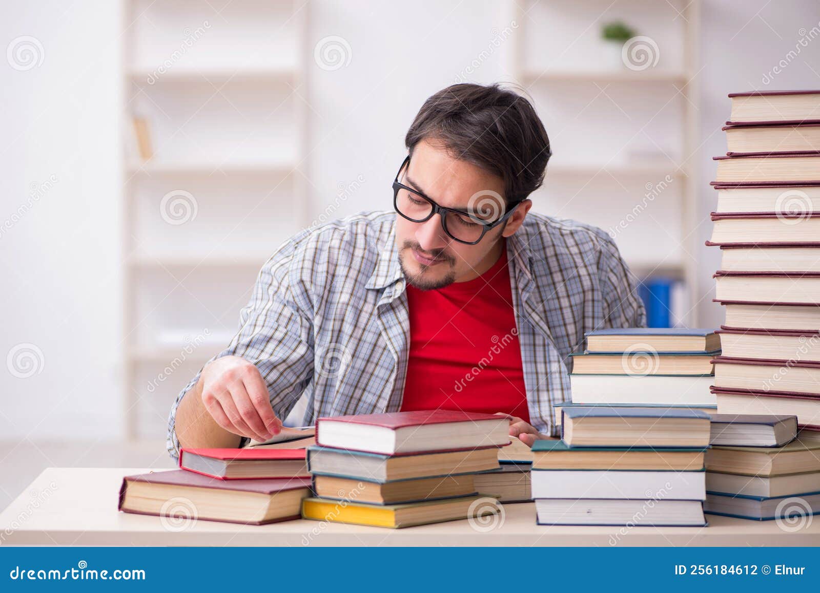 Young Male Student and Too Many Books in the Classroom Stock Photo ...