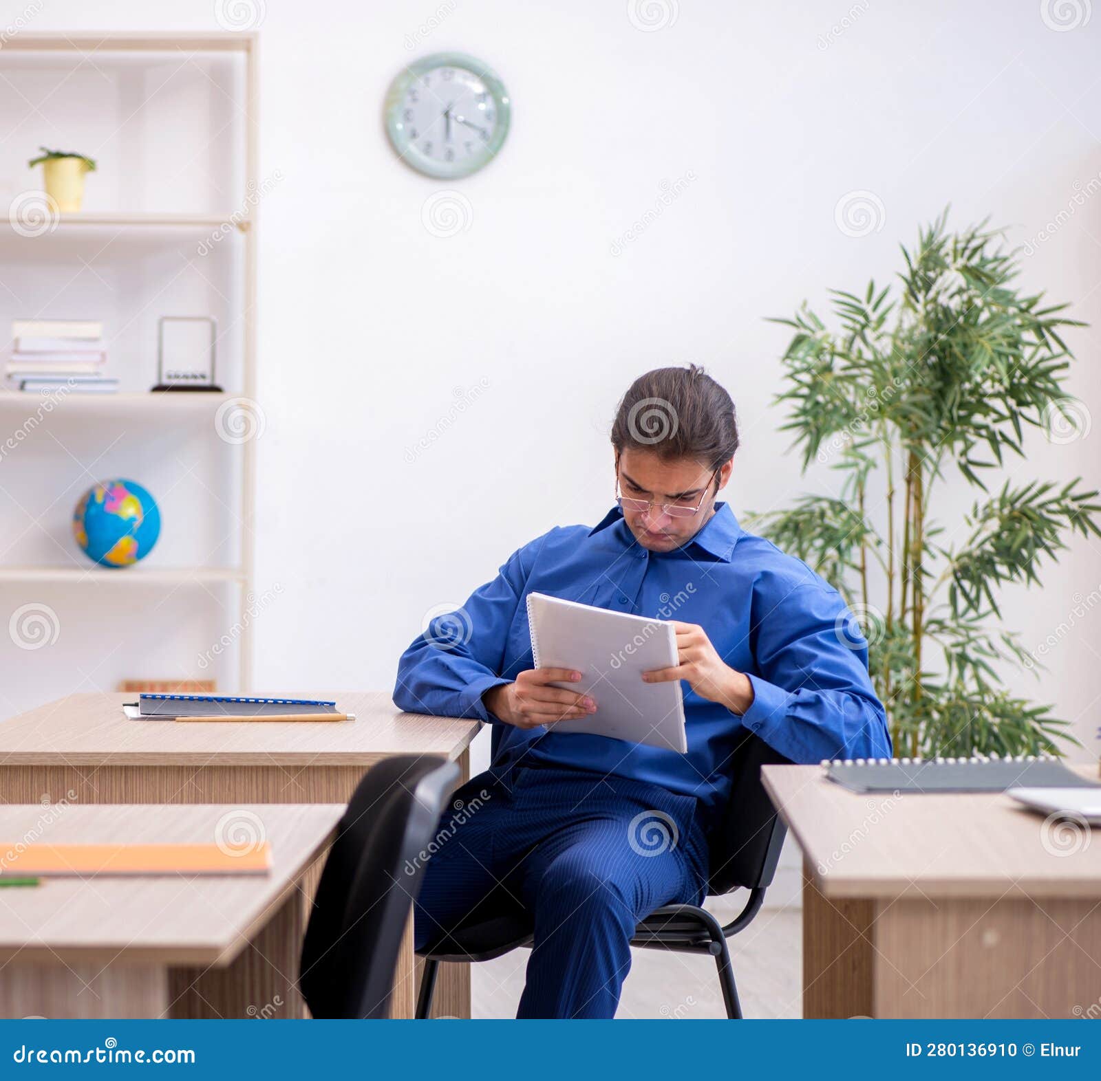 Young Male Teacher Checking Notes in the Classroom Stock Photo - Image ...
