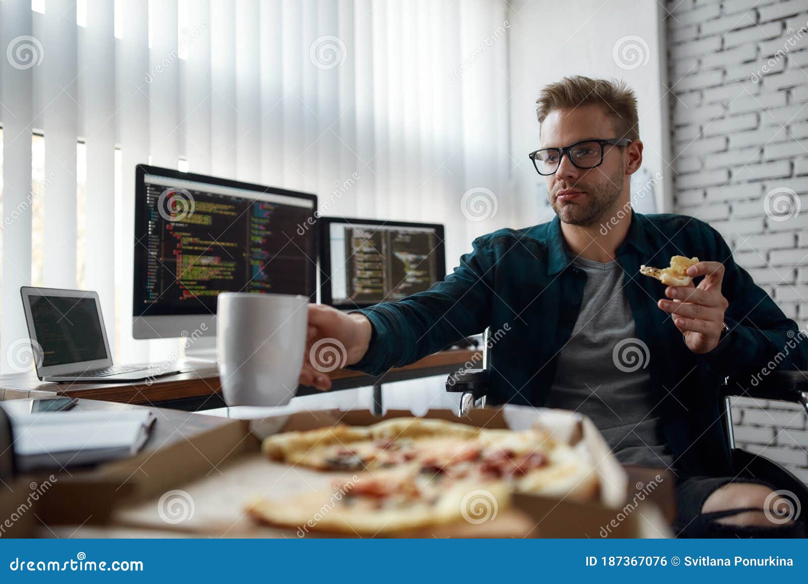 Coffee Break. Young Male Web Developer in a Wheelchair Eating Pizza and ...