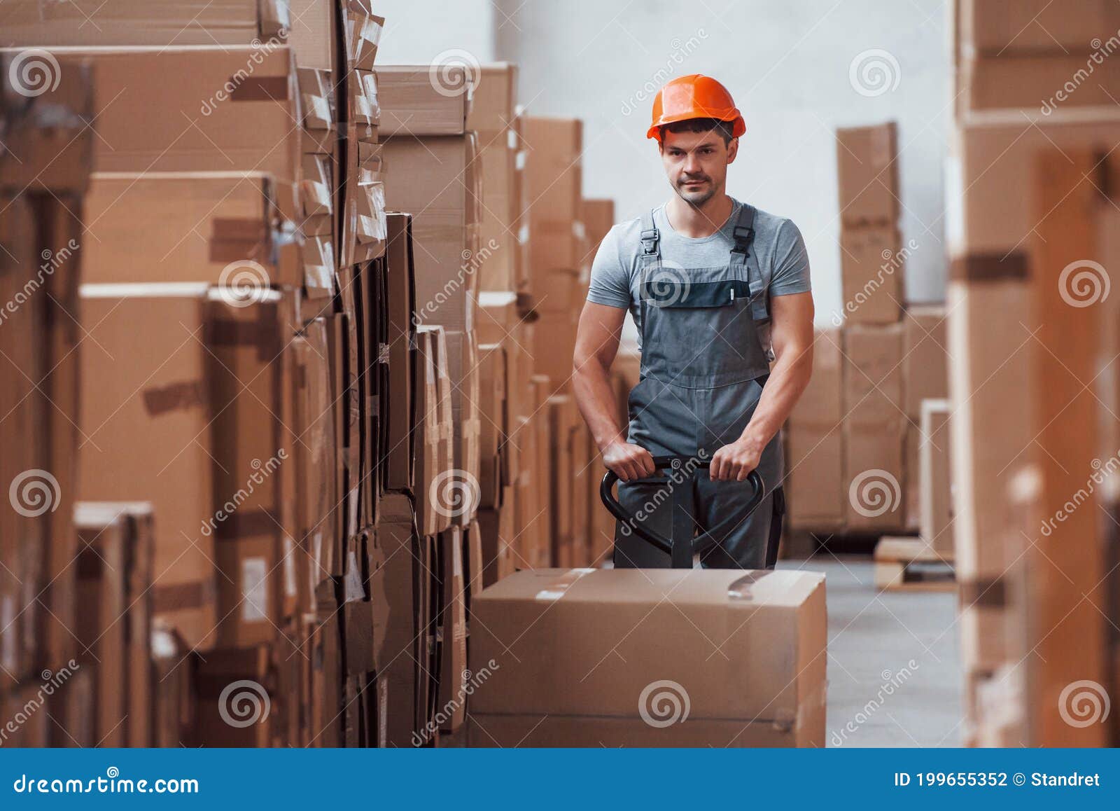 Young Male Worker in Uniform is in the Warehouse with Pallet Truck ...