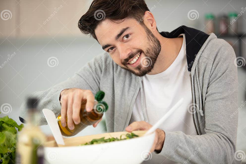 Young Man Adding Spice To Salad and Smiling Stock Photo - Image of ...