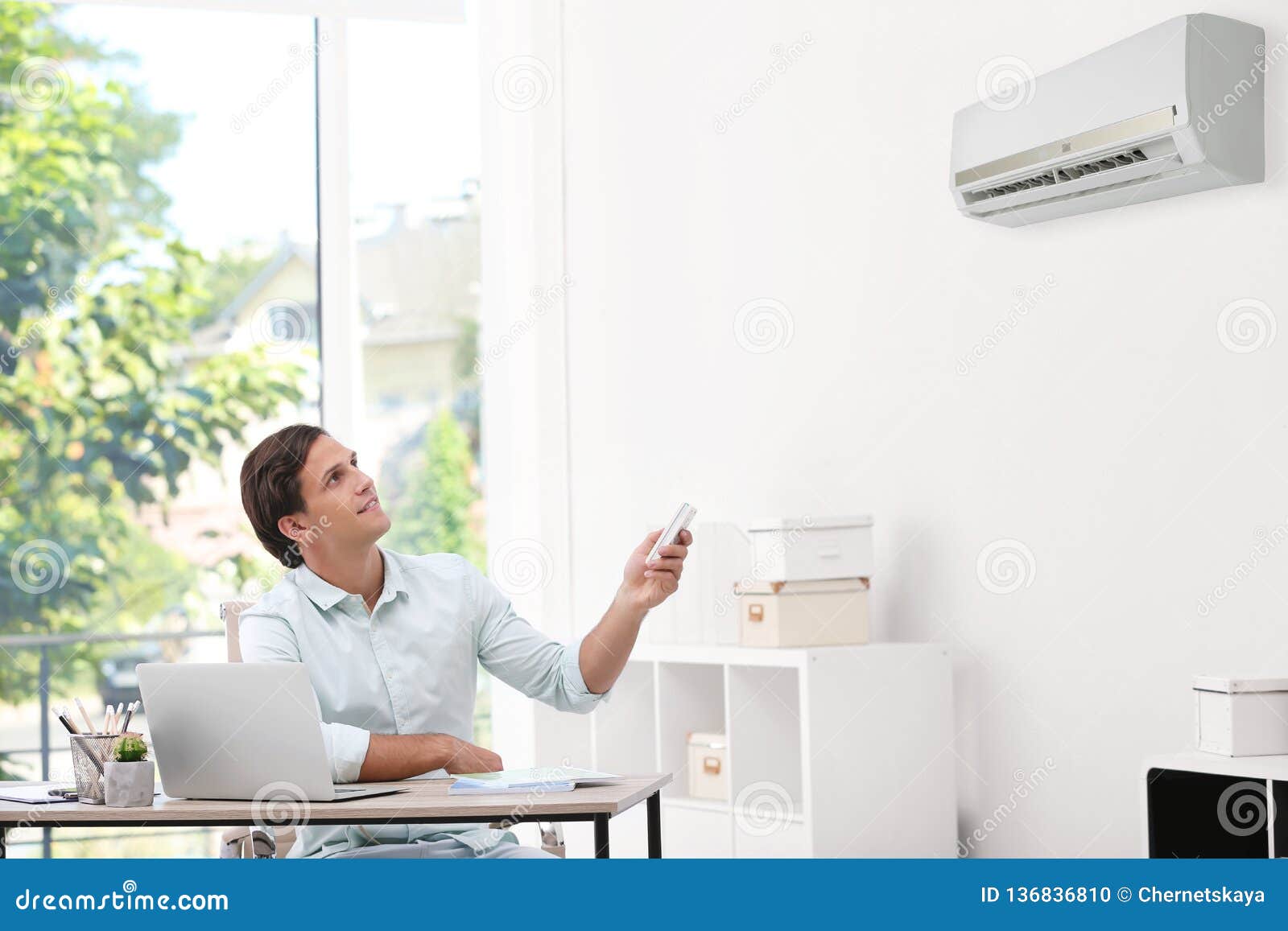 Young Man with Air Conditioner Remote in Office Stock Photo - Image of ...