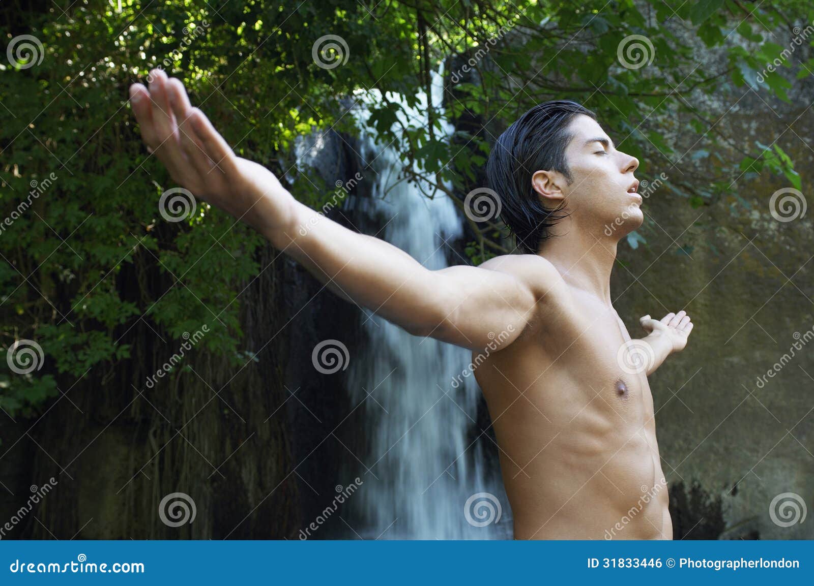 Young Man with Arms Outstretched Meditating Against Waterfall Stock ...