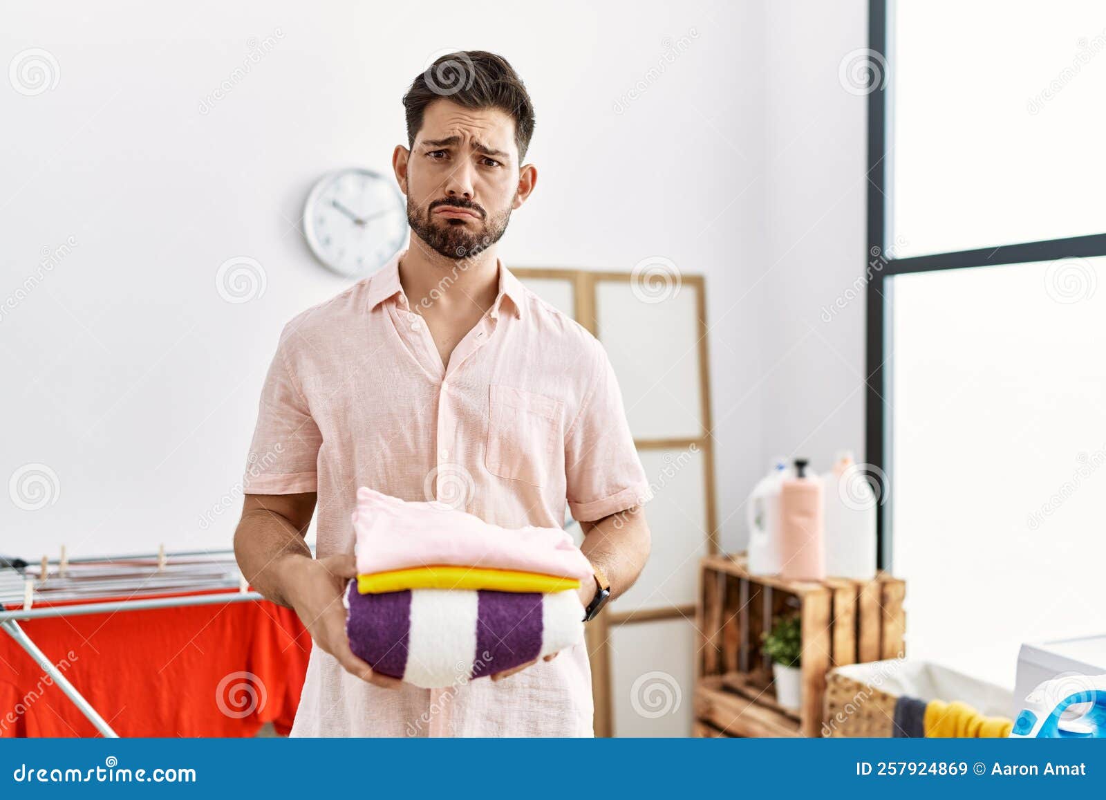 Young Man with Beard Holding Folded Laundry after Ironing Depressed and ...