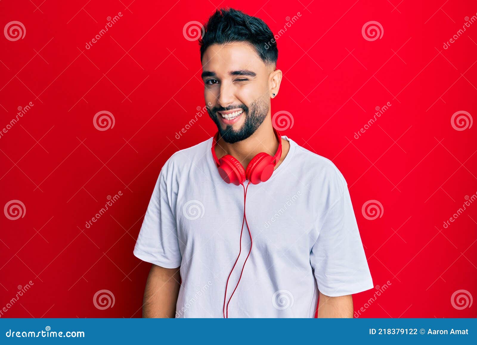 Young Man With Beard Listening To Music Using Headphones Winking