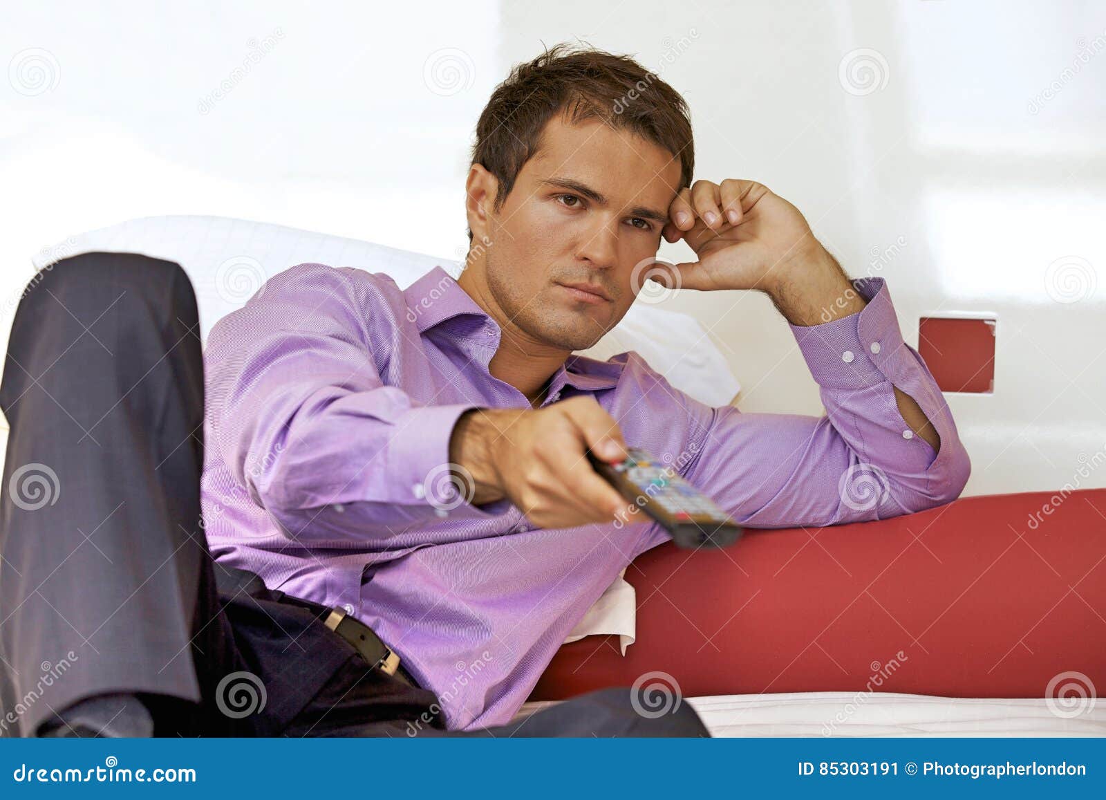 Young Man on Bed Using Remote Control Stock Image - Image of room ...