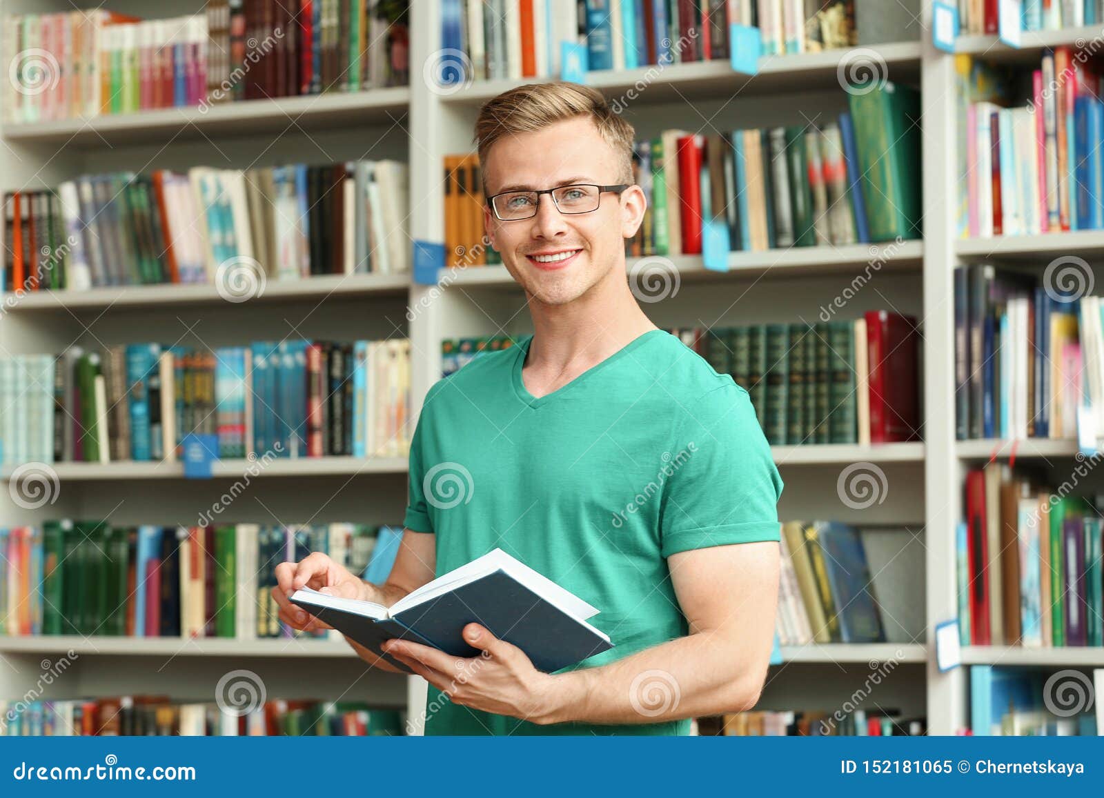 Young Man with Book Near Shelving Unit Stock Image - Image of ...