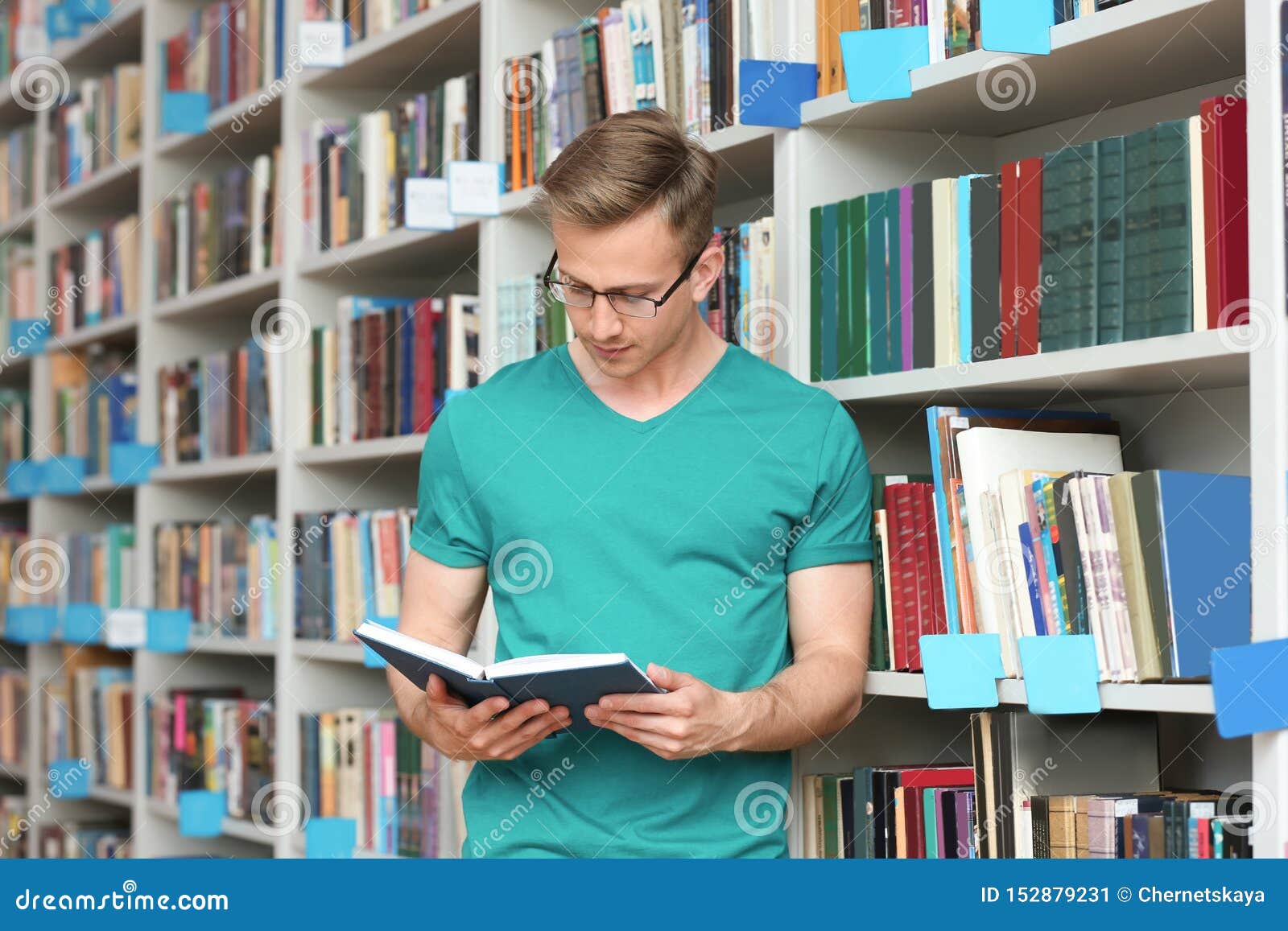 Young Man with Book Near Shelving Unit Stock Image - Image of education ...