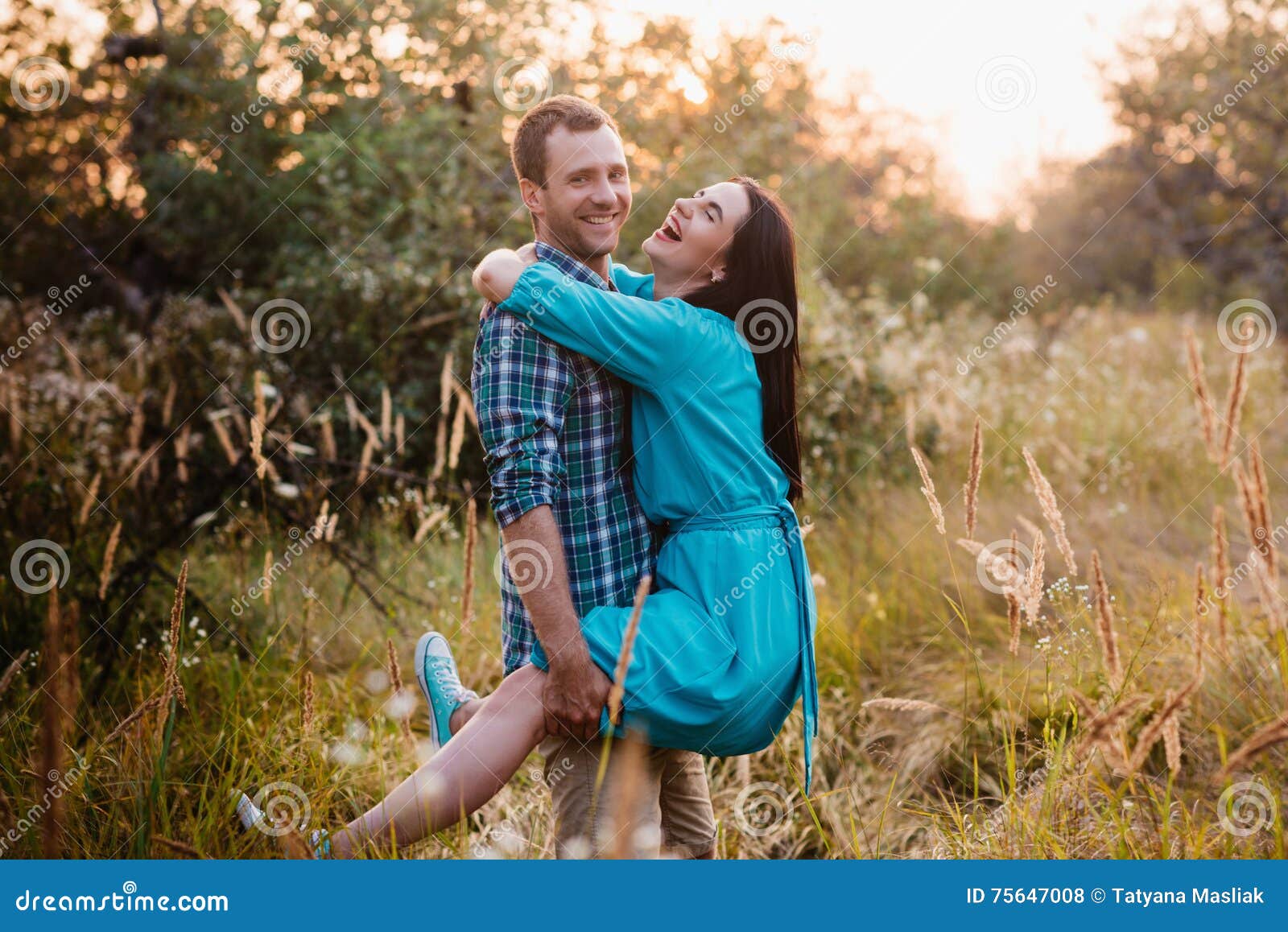 Young Man Carries In His Arms A Young Attractive Girl In A Park Stock