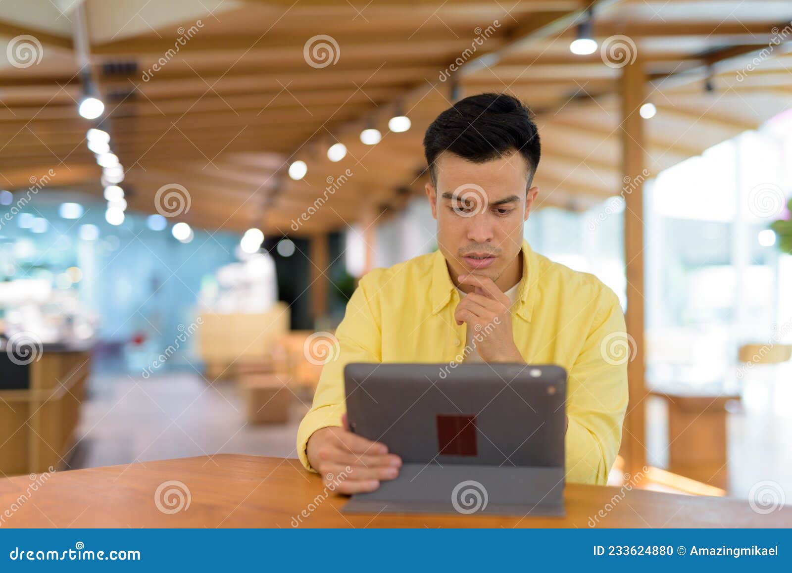 Young Man at Coffee Shop Thinking and Using Digital Tablet Computer ...