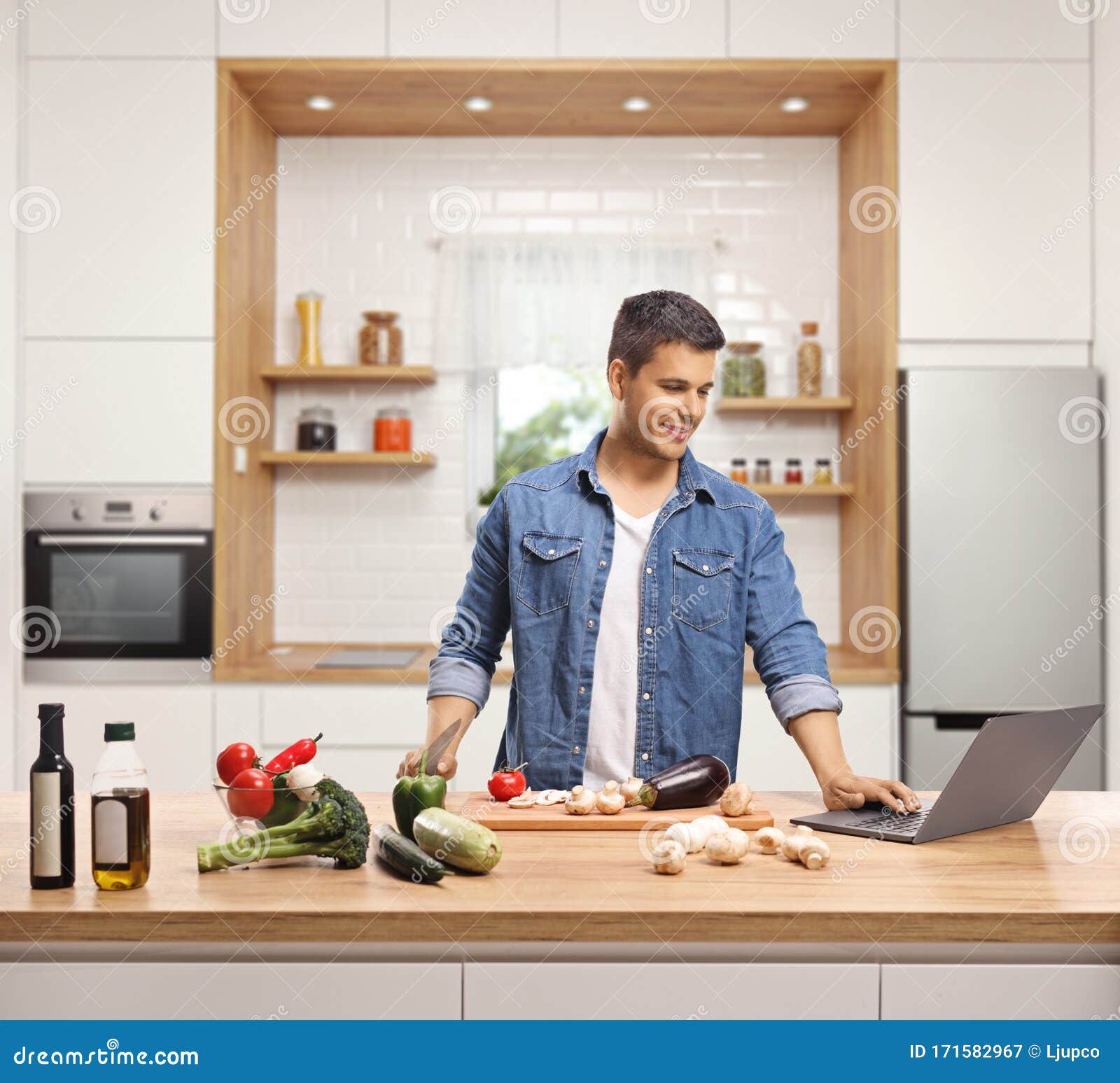 Young Man Cooking in a Kitchen with a Laptop Stock Image - Image of ...