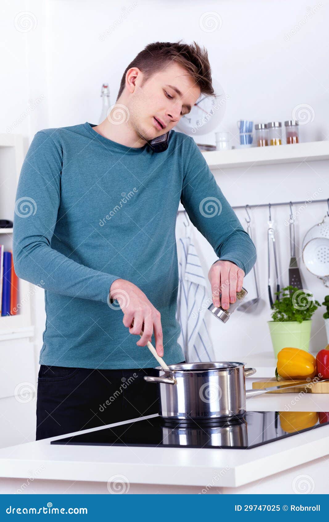 Young Man Cooking a Meal and Talking on the Phone in the Kitchen Stock ...