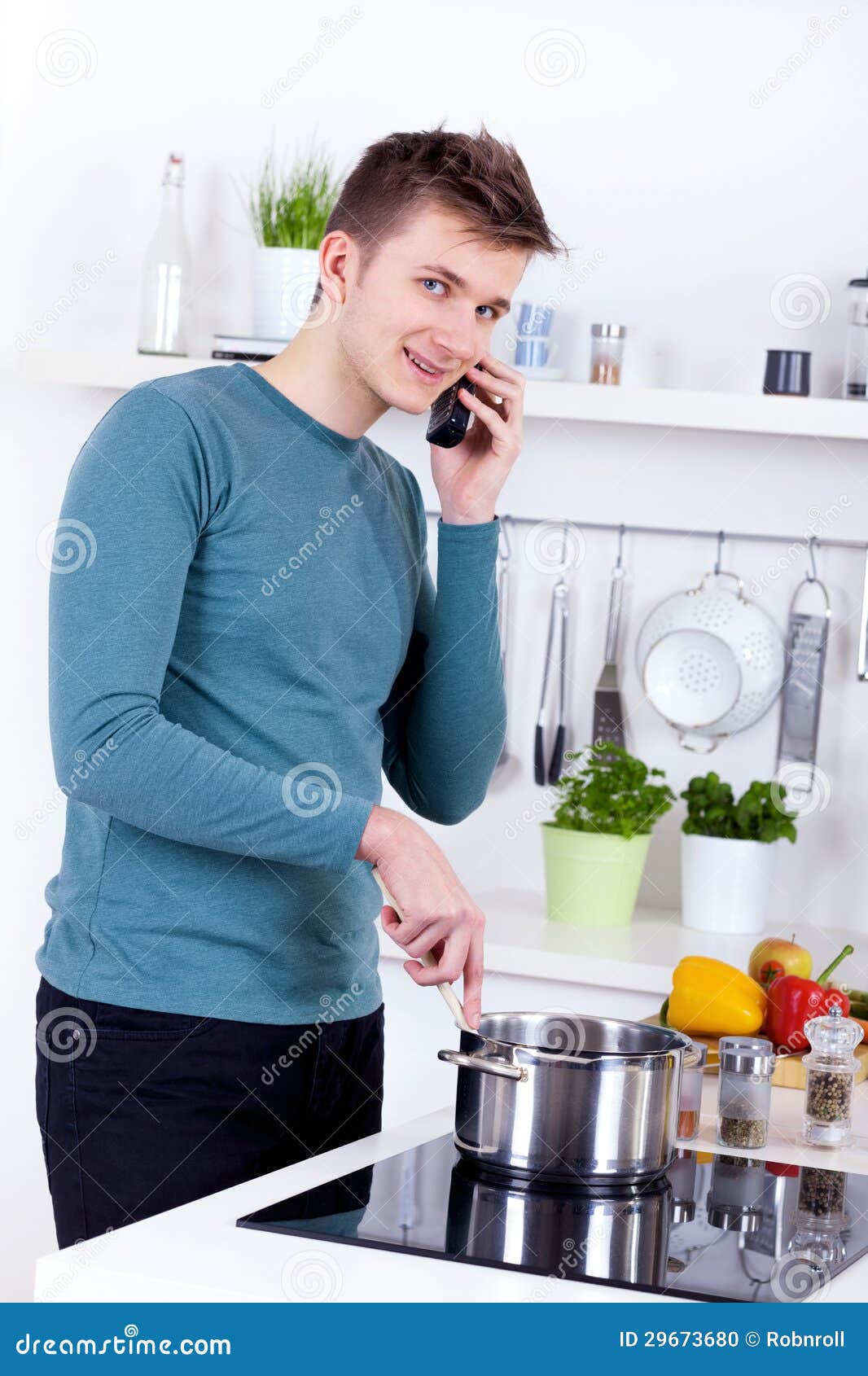 Young Man Cooking a Meal and Talking on the Phone in the Kitchen Stock ...