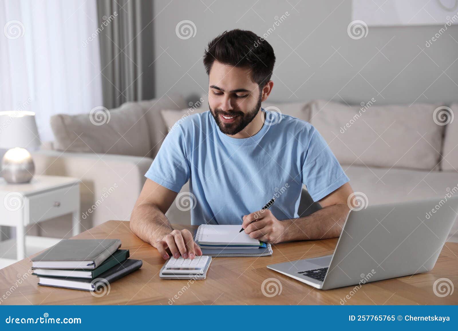 Young Man Counting on Calculator during Webinar at Table in Room Stock ...