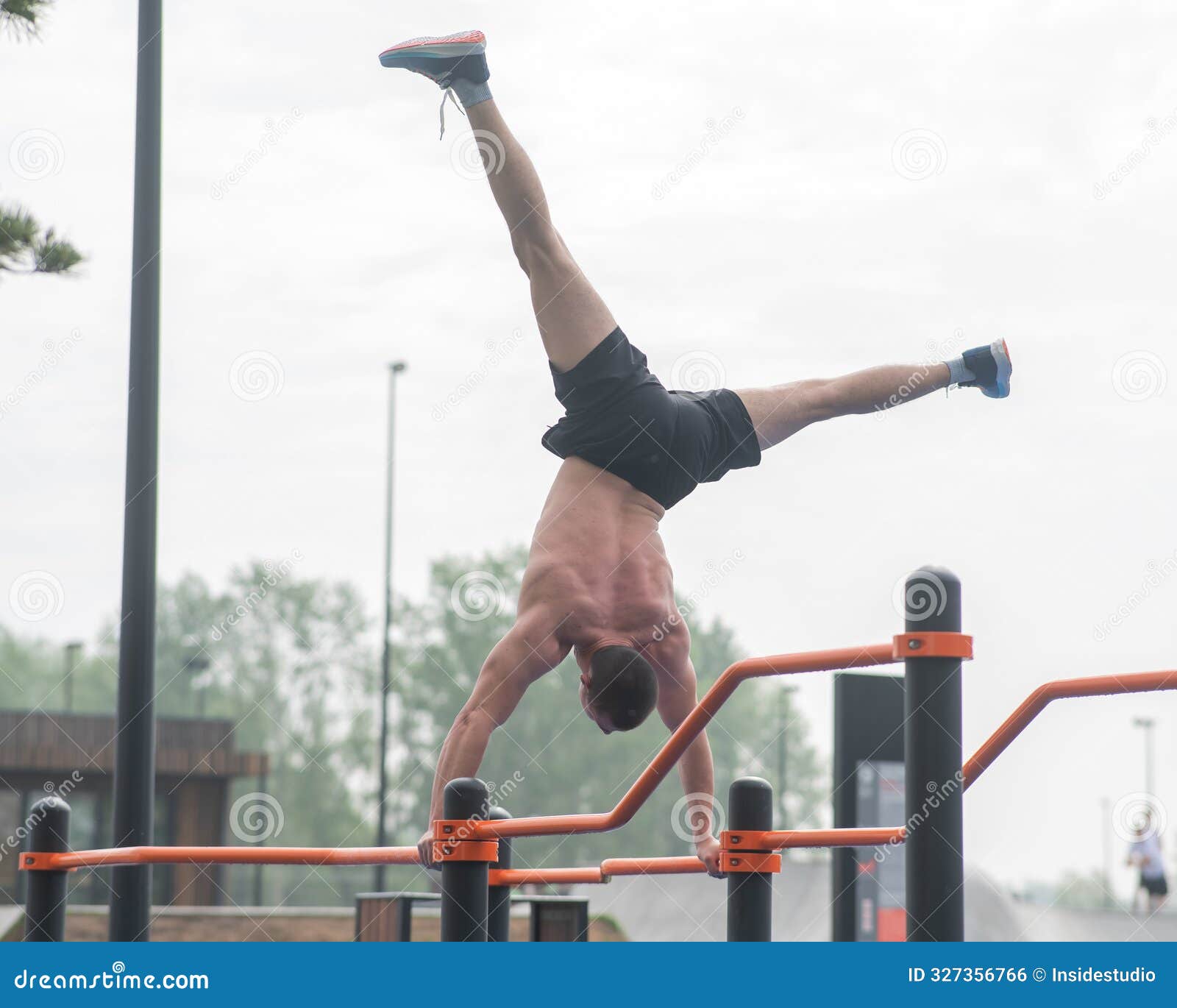 A Young Man Doing a Handstand on Parallel Bars Outdoors. Workout. Stock ...