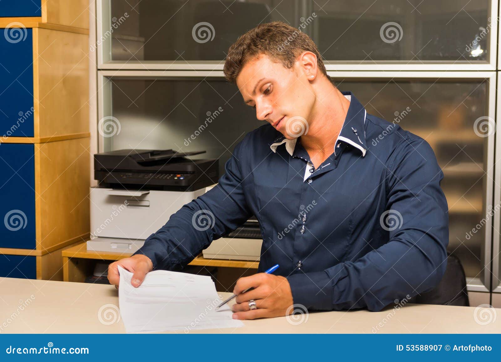 Young Man Doing Paperwork at Office Desk, Showing Stock Image - Image ...