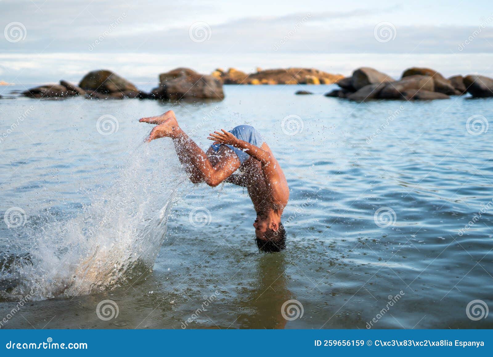 Young Caucasian Man Doing a Somersault in the Beach Inside the Water ...