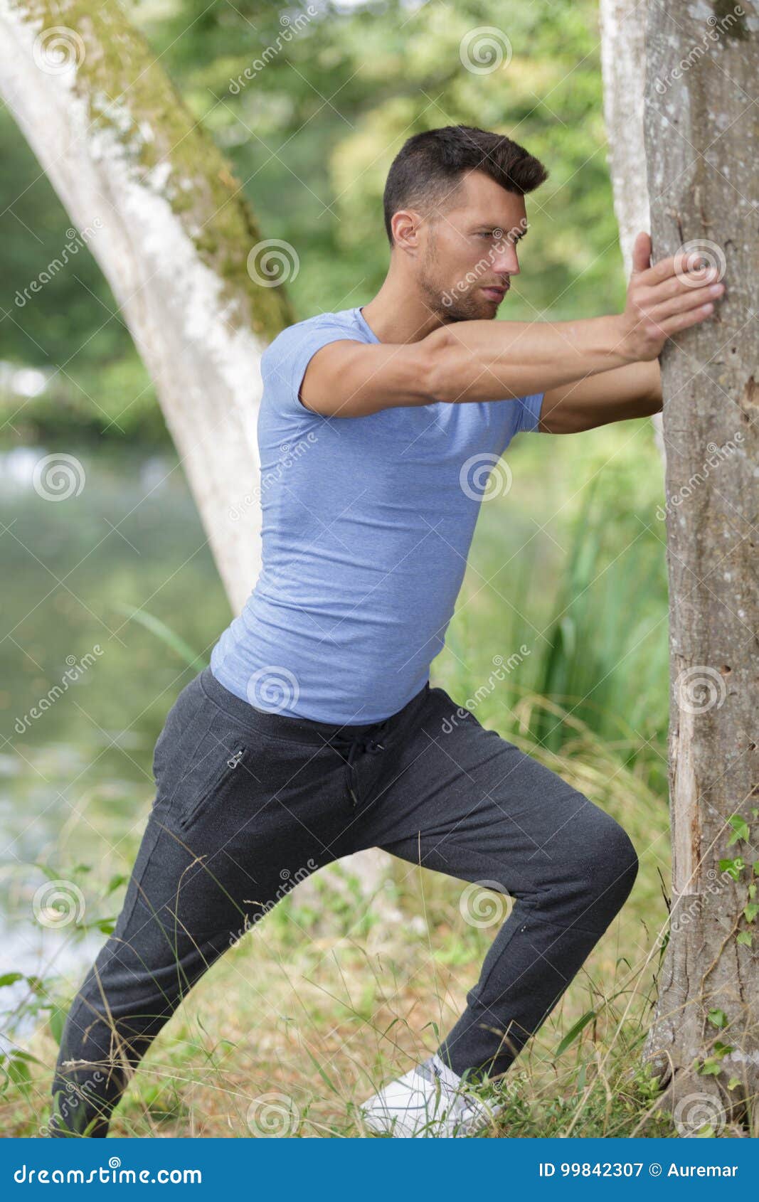 Young Man Doing Stretching Against Tree in Park Stock Image - Image of ...
