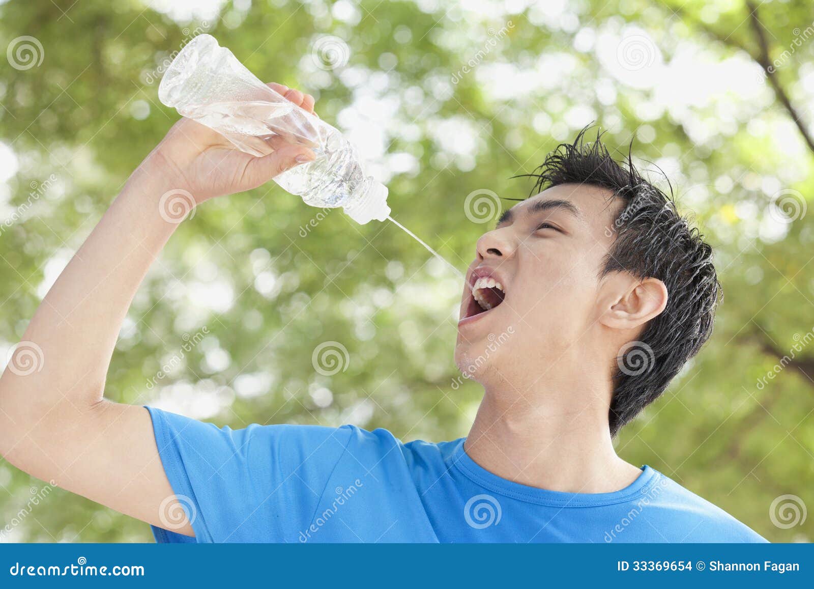Young Man Drinking Bottled Water in Park Stock Photo - Image of cold ...