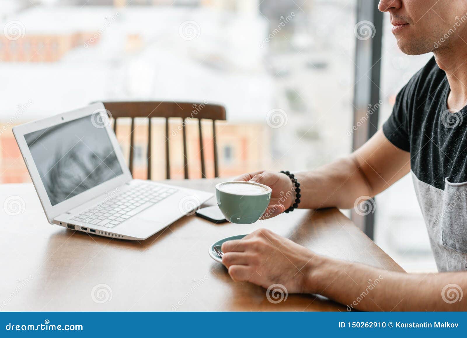 Young Man Drinking Coffee from a Cup. Freelancer Work on Netbook in ...