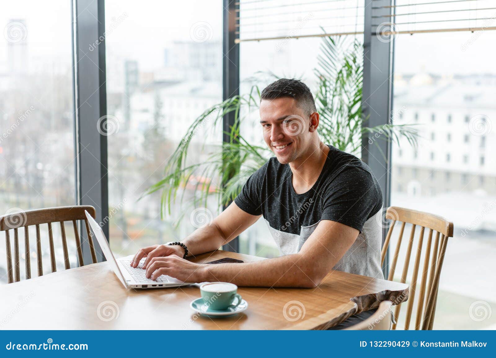 Young Man Drinking Coffee from a Cup. Freelancer Work on Netbook in ...