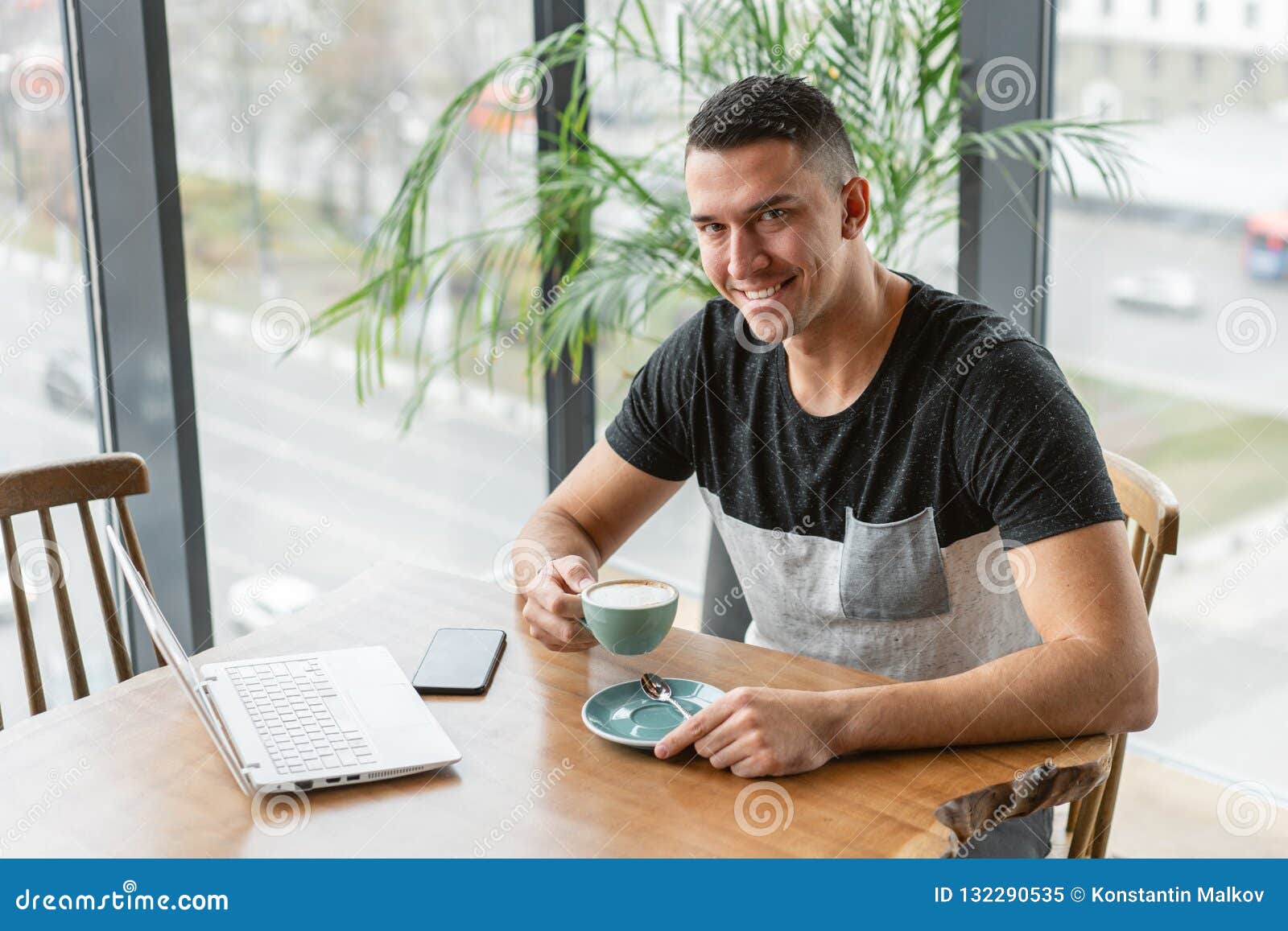 Young Man Drinking Coffee from a Cup. Freelancer Work on Netbook in ...